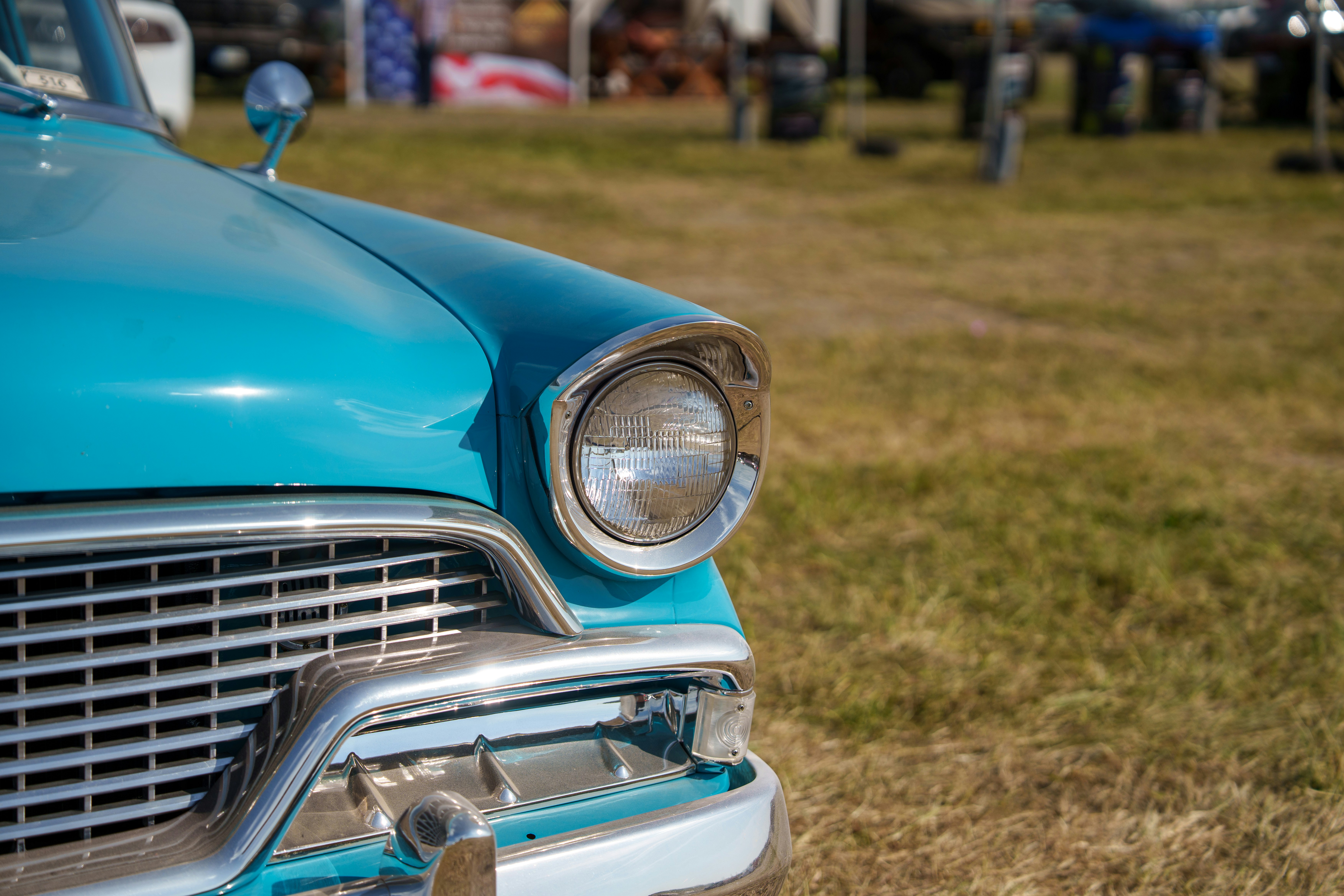 Turquoise Classic: Chrome Grille and Headlight of a Vintage Car