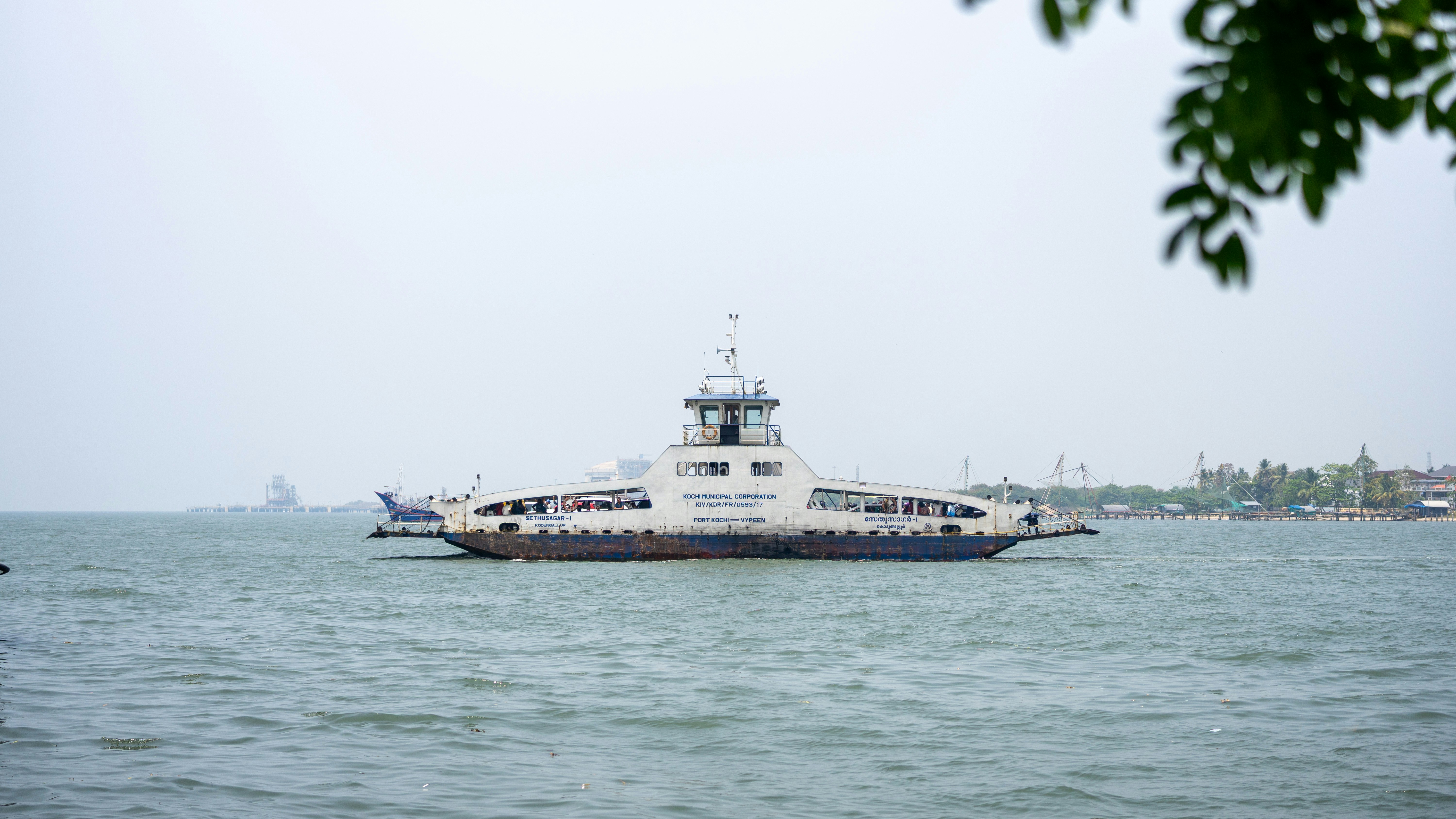 White ferry gliding across a calm harbor as shoreline fades into haze