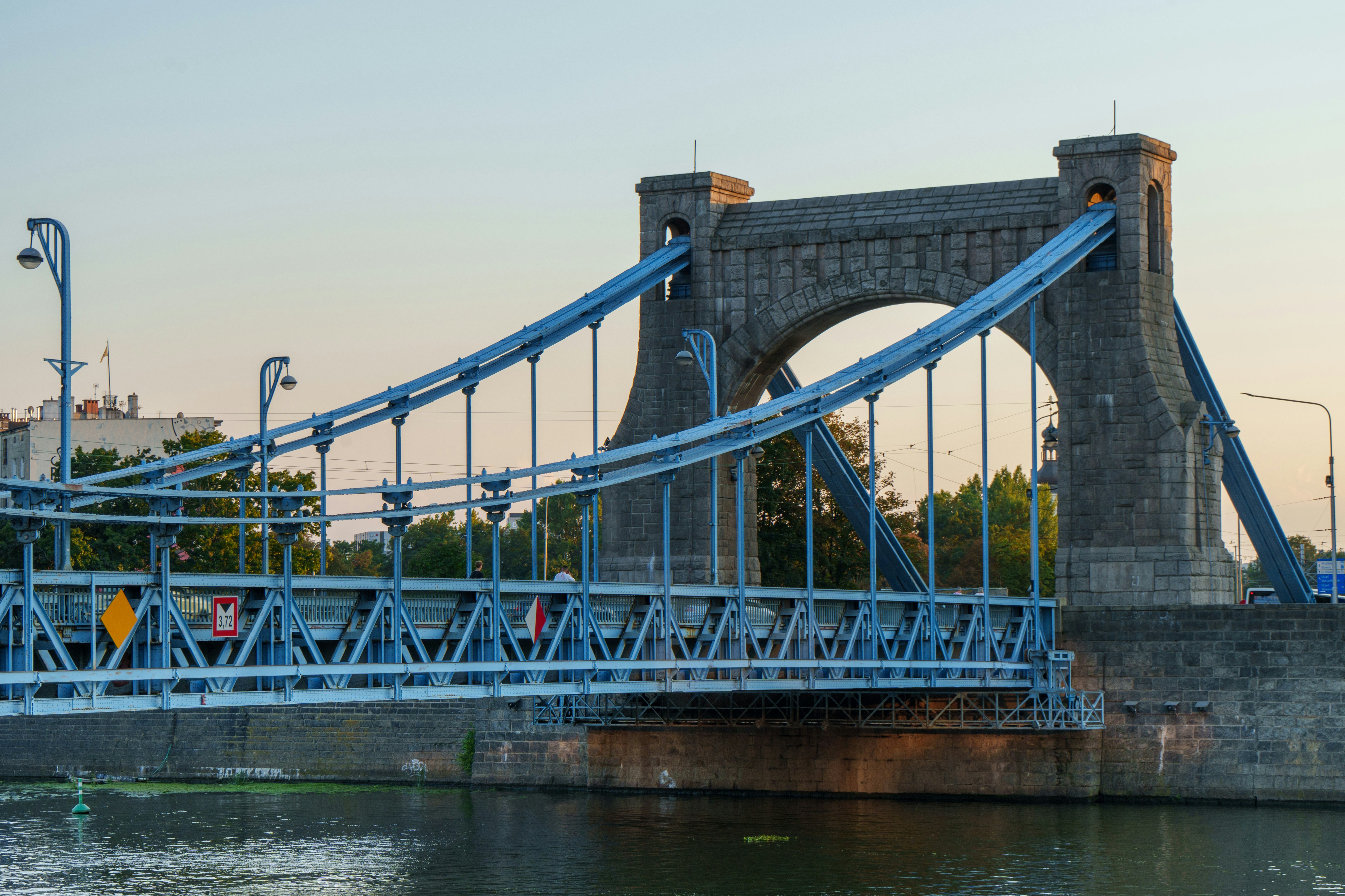 Blue Suspension Bridge Crossing a Quiet River at Dusk