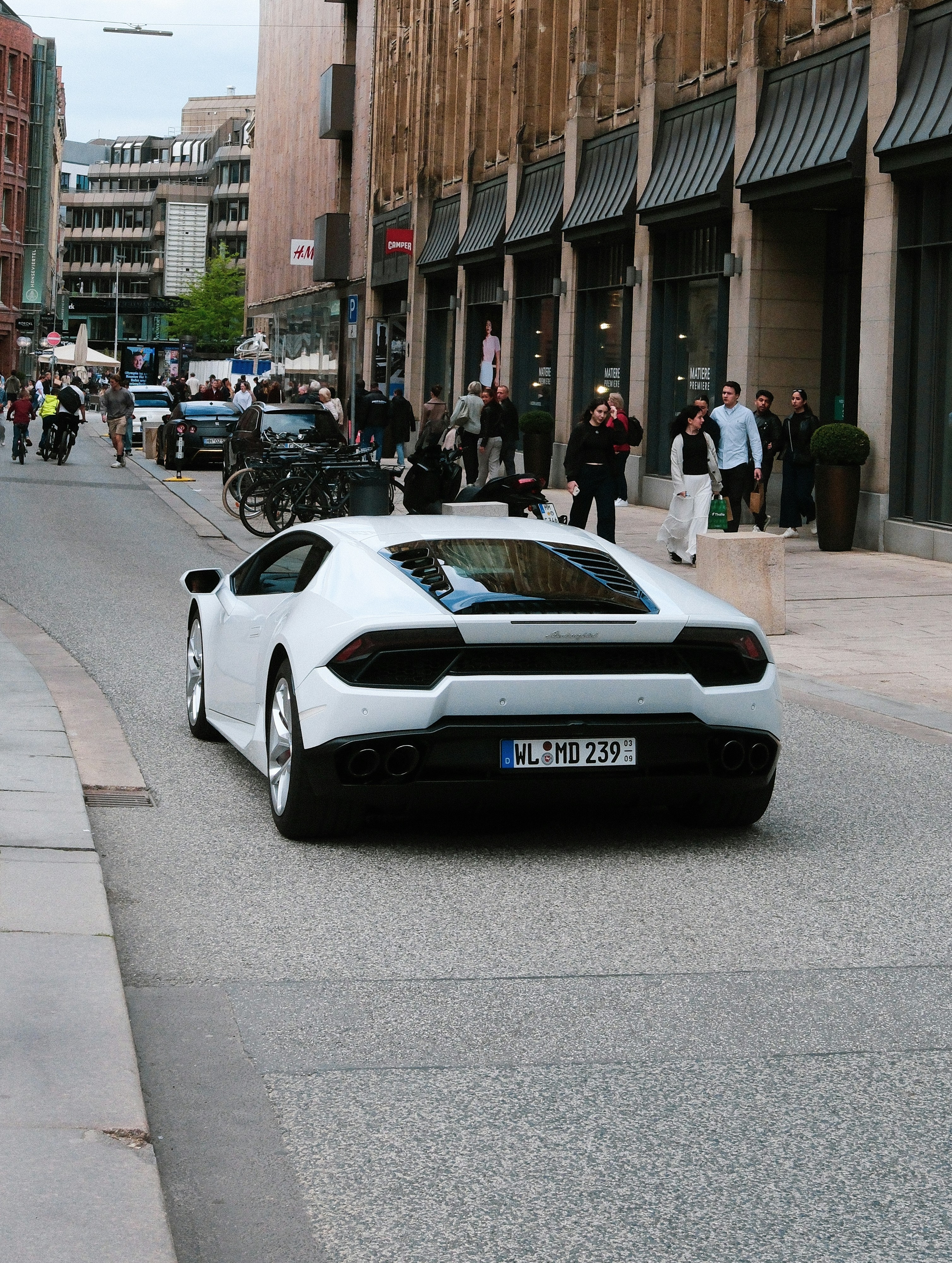 White Lamborghini on a City Street Amid Curious Passersby