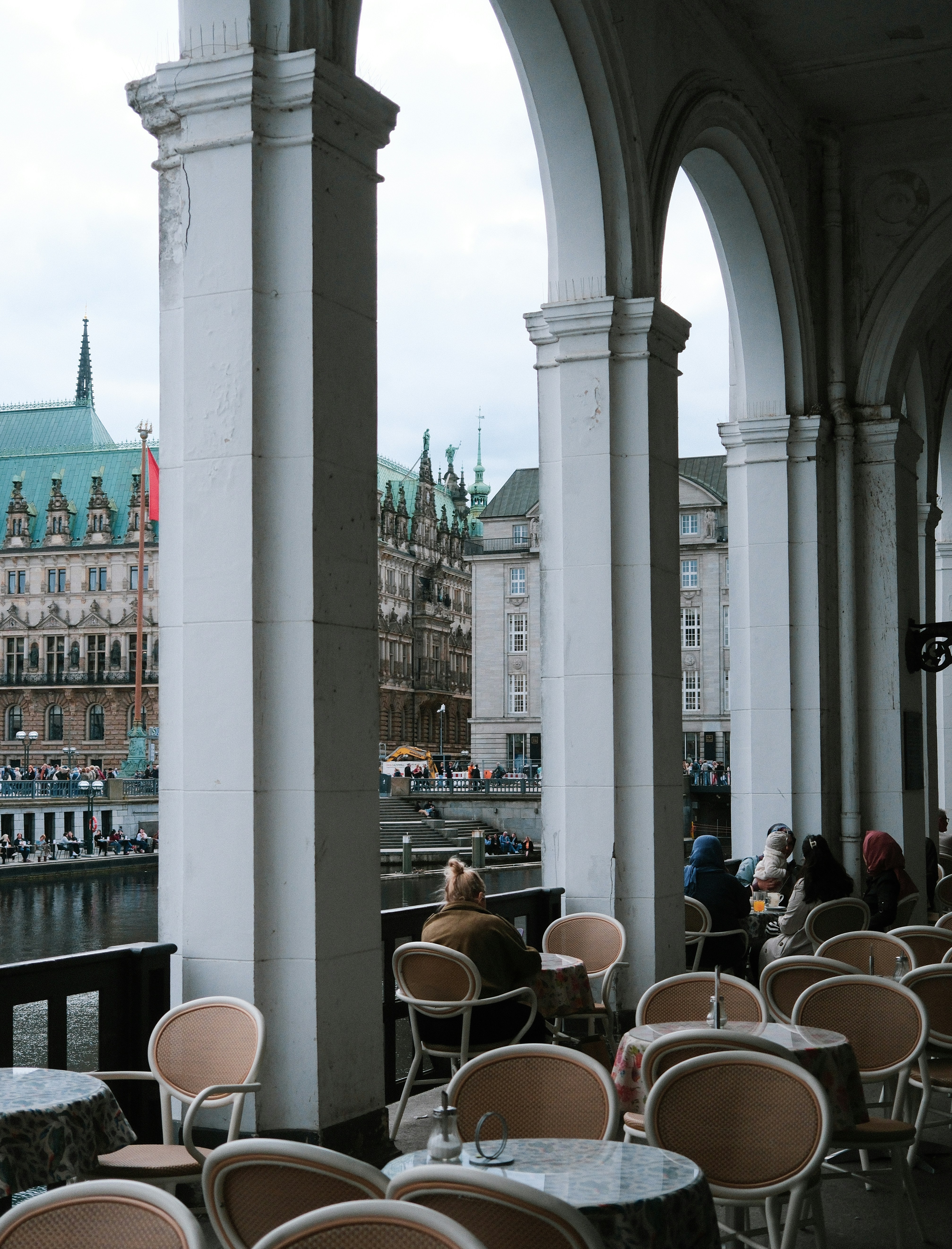 Arcade of Light: Café Rows Under White Columns by a City Canal