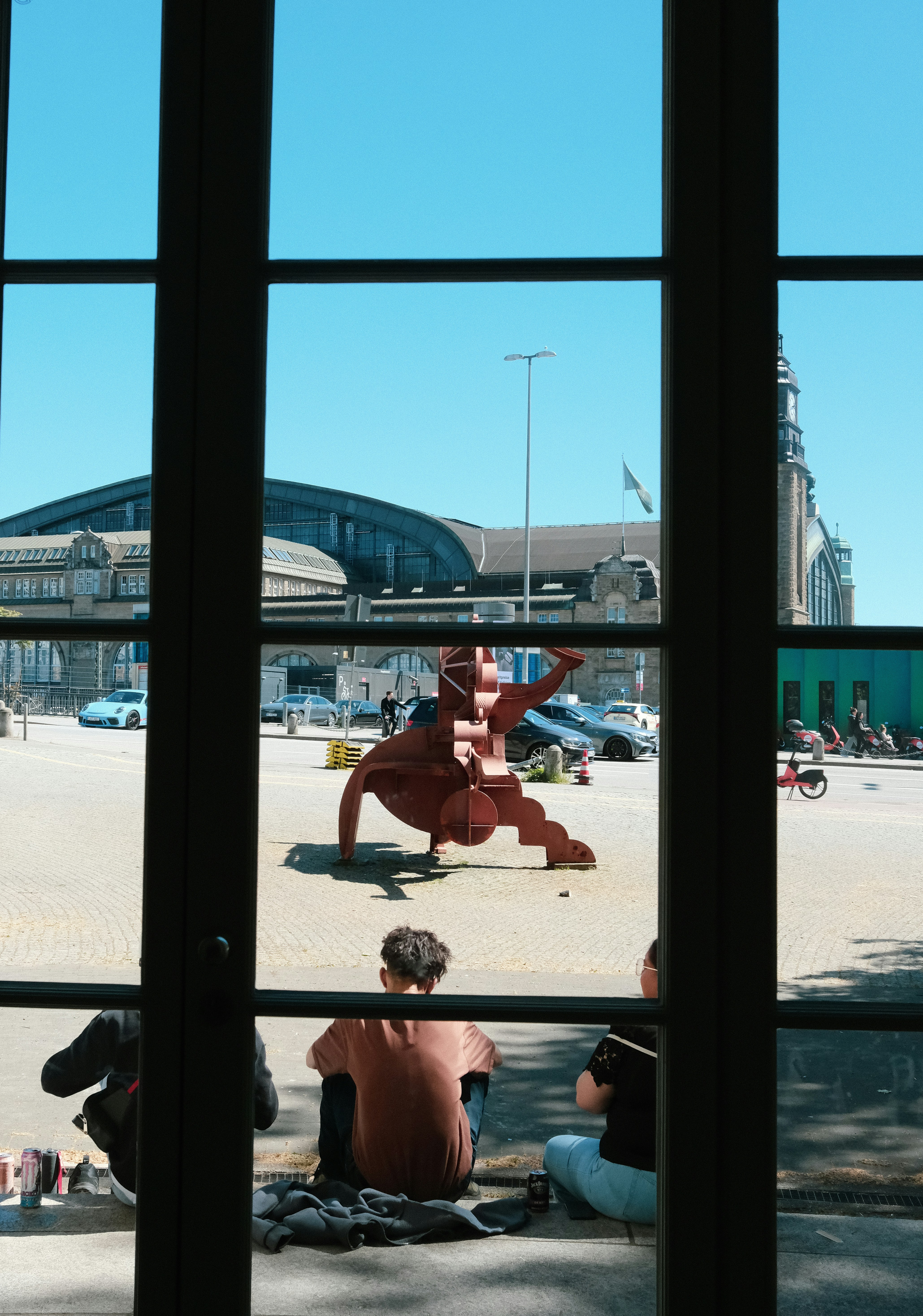 Windows to the Square: Red Sculpture Framed by Morning Glass