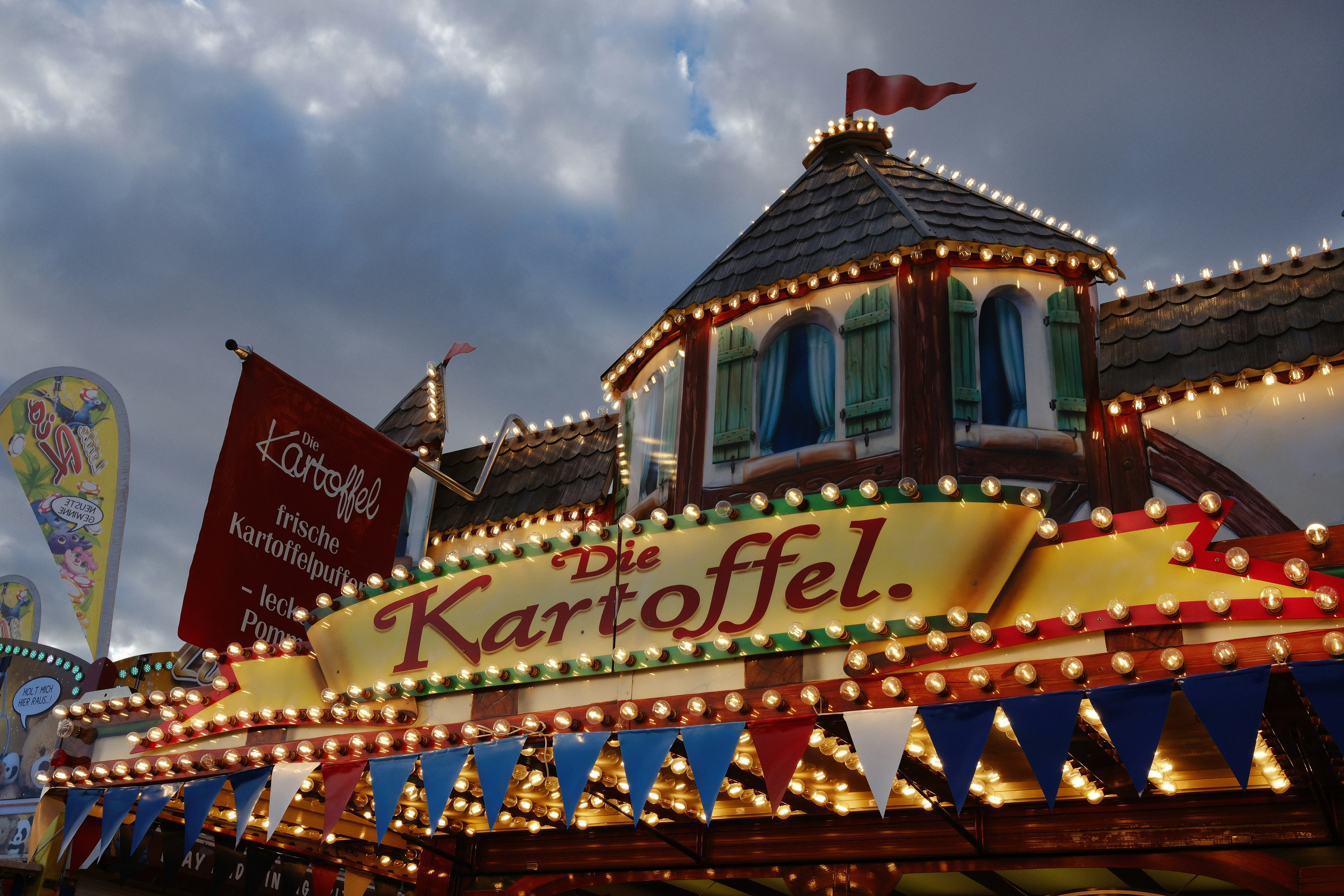 Glowing Fairground Signage: Die Kartoffel Under Festoon Lights