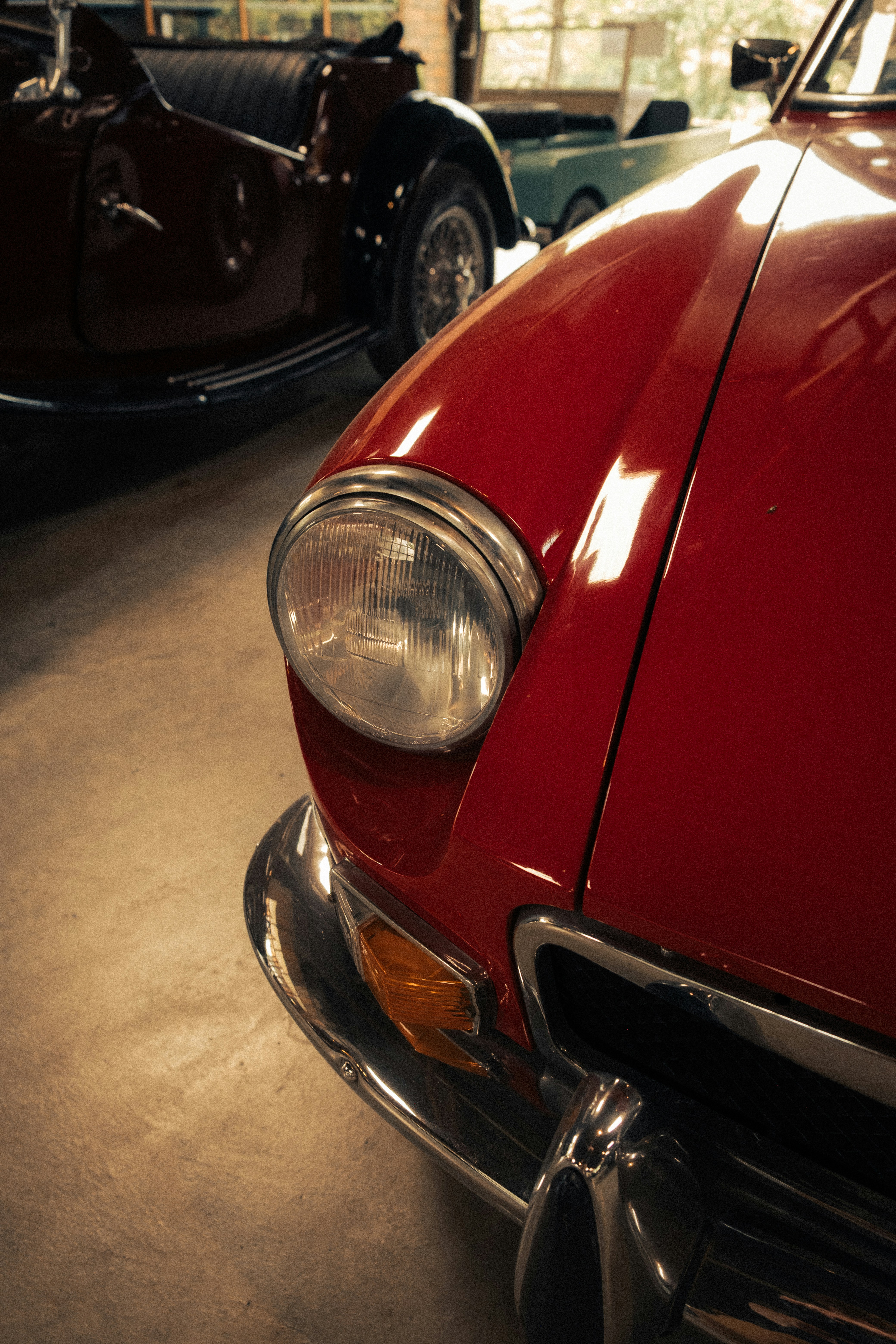 Crimson Headlight Gaze: Classic Car Front in a Vintage Garage