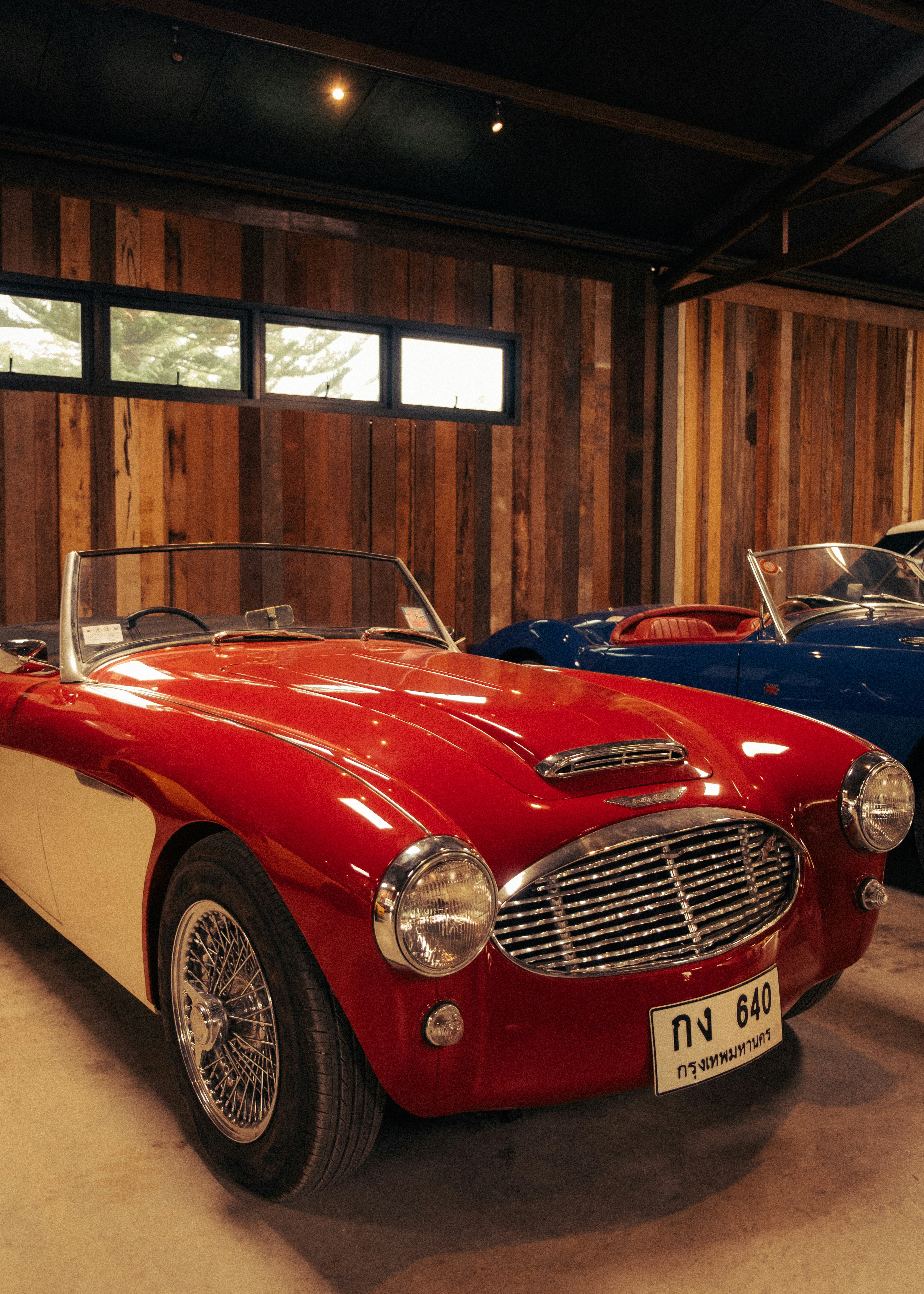Red Roadster in warm-toned showroom with wood paneling