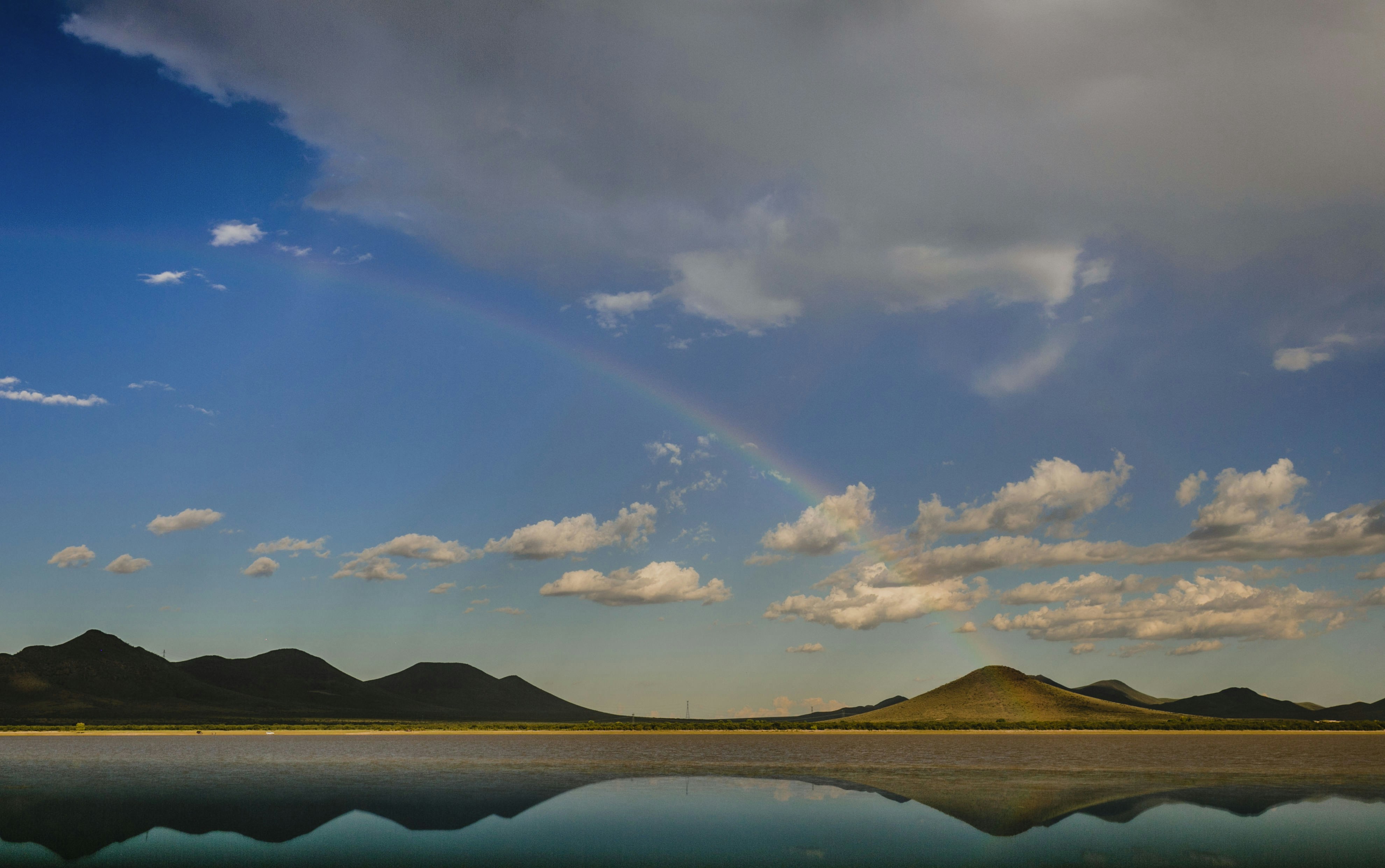 Rainbow over silent dunes: a mirrored horizon