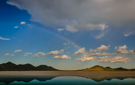 Rainbow over silent dunes: a mirrored horizon