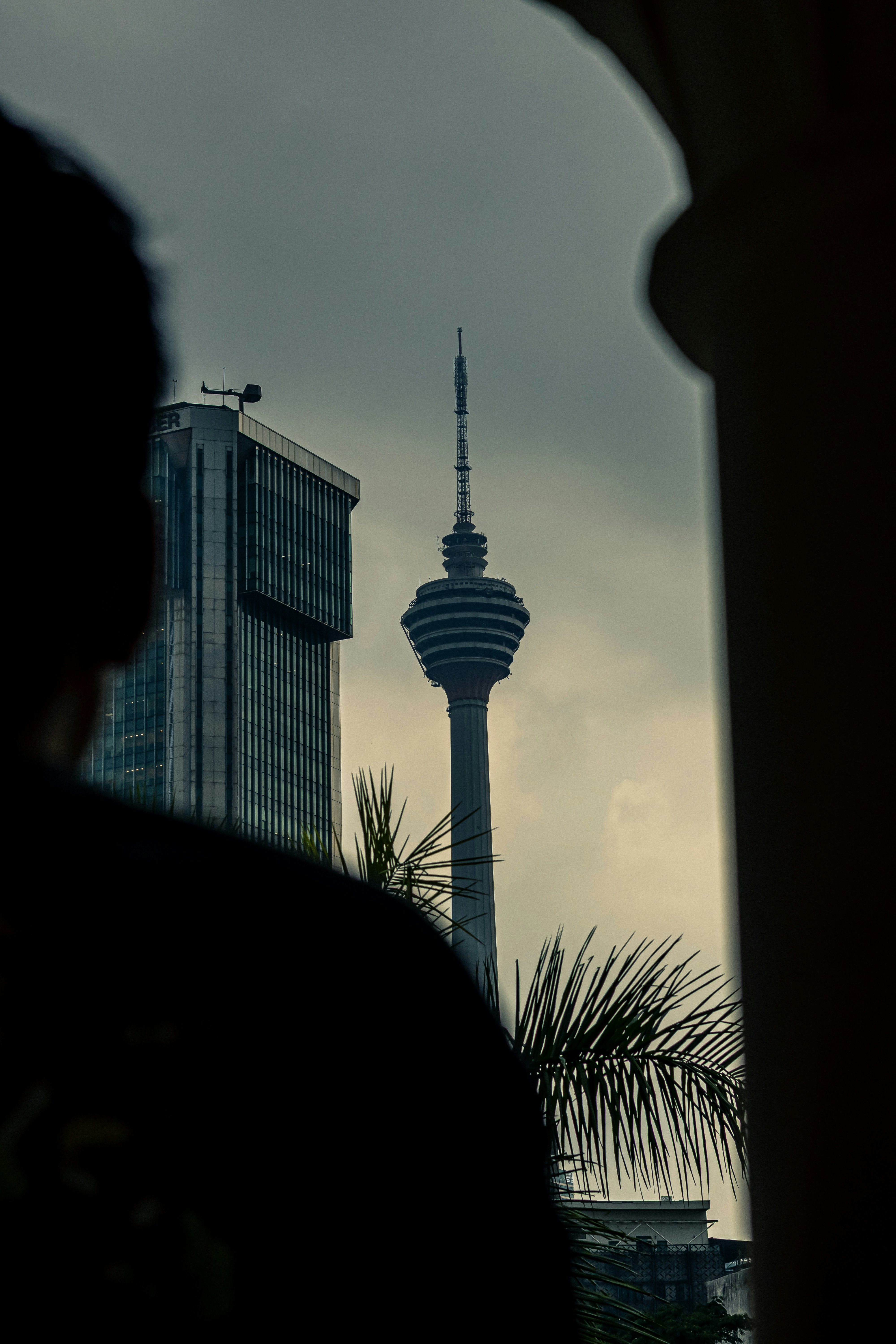 City Tower in a Framed Gap: Skyline Through a Shadowed Arch