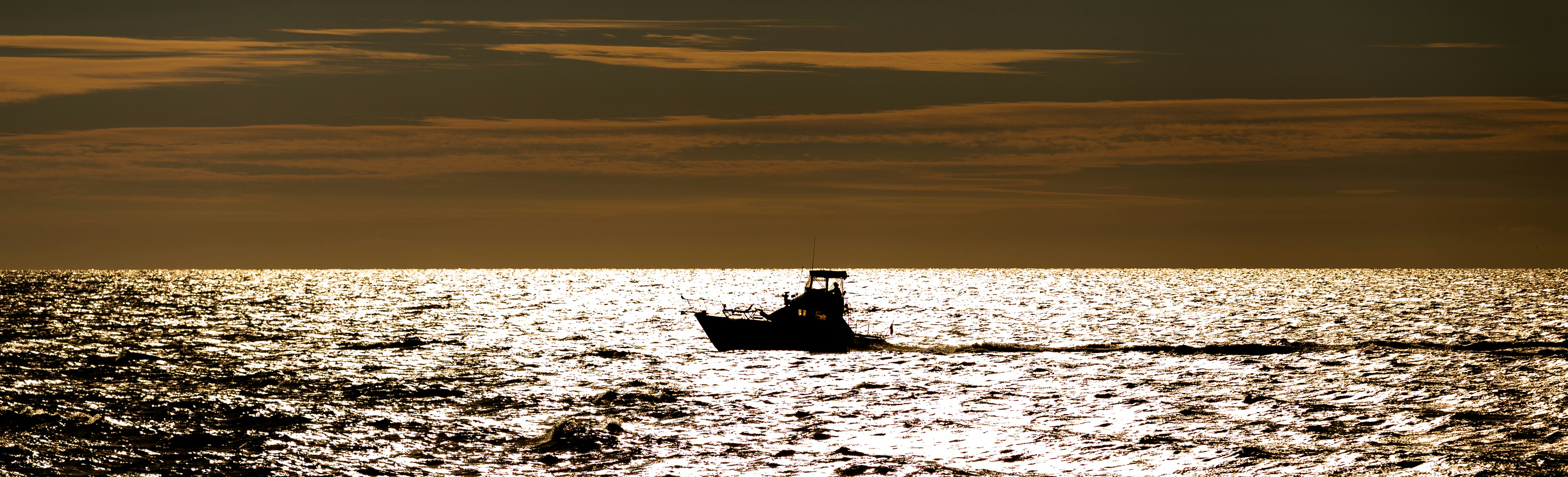 Silhouette on the Glowing Horizon: A lone boat at sundown