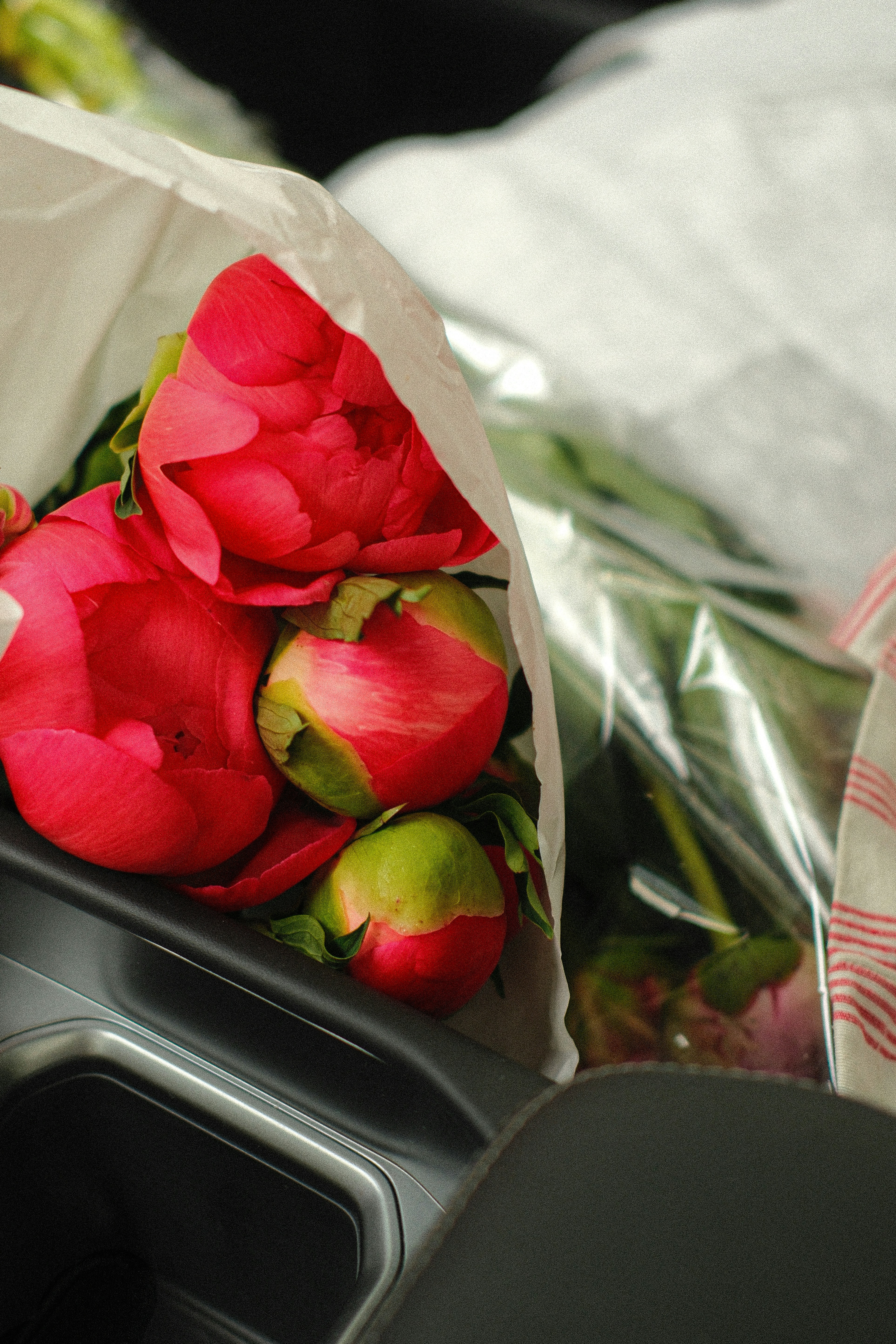 Pink peonies in a white bag with red striped bag