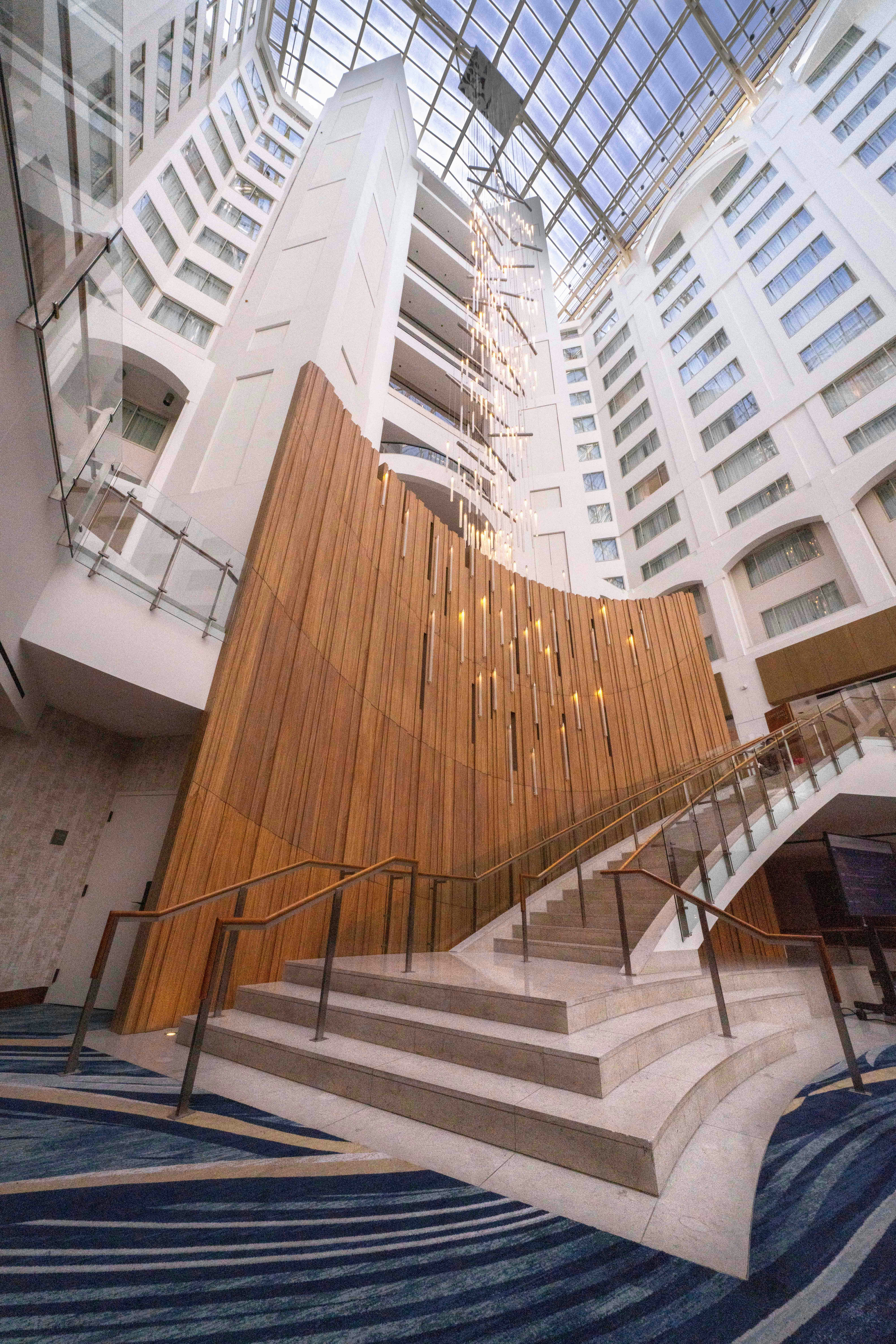 Vertical Serenade: Staircase of Warm Wood in a Glass Atrium