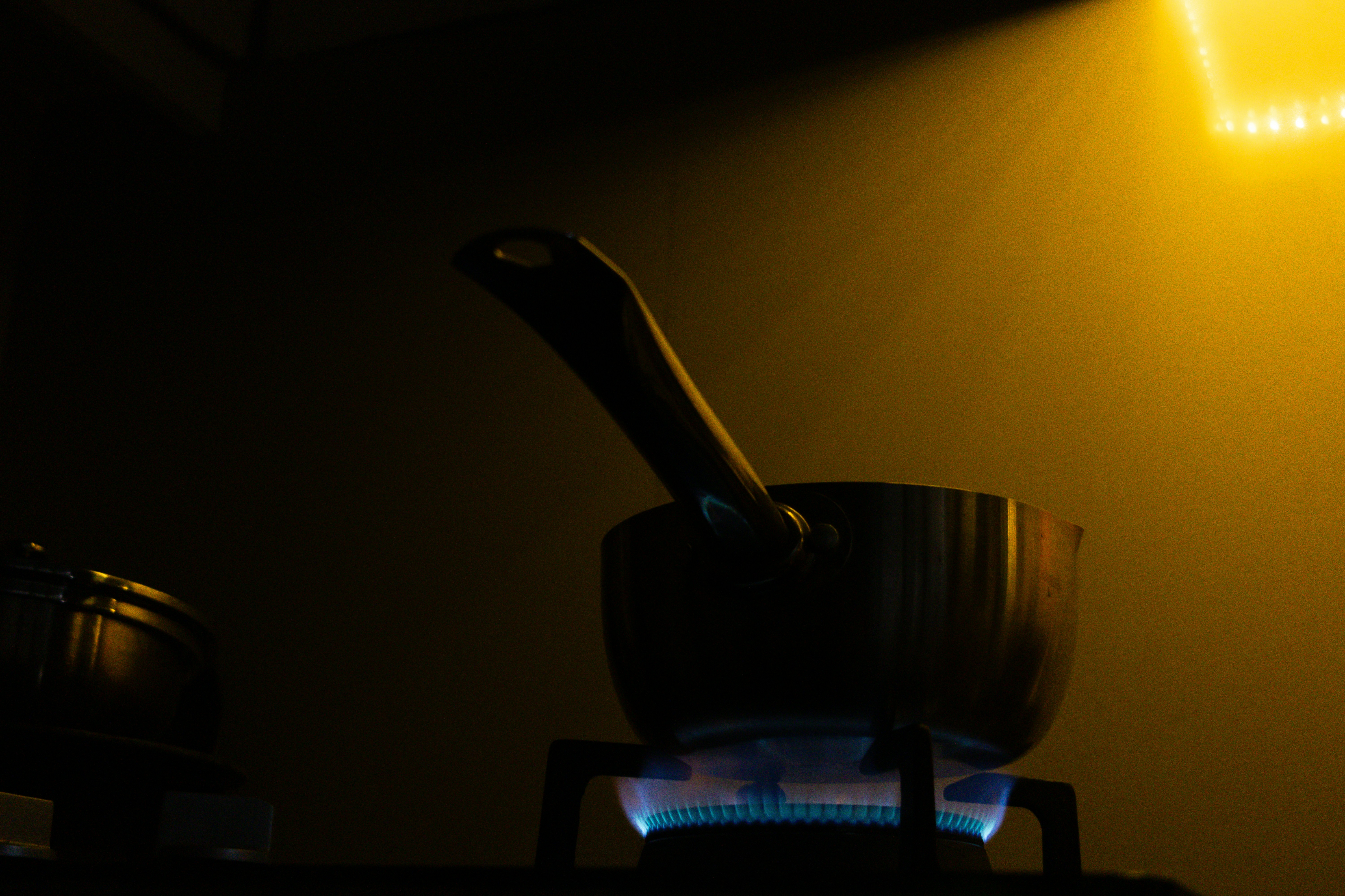 Low Flame, Quiet Kitchen: A Brass Pot on a Gas Burner in Dim Evening Light