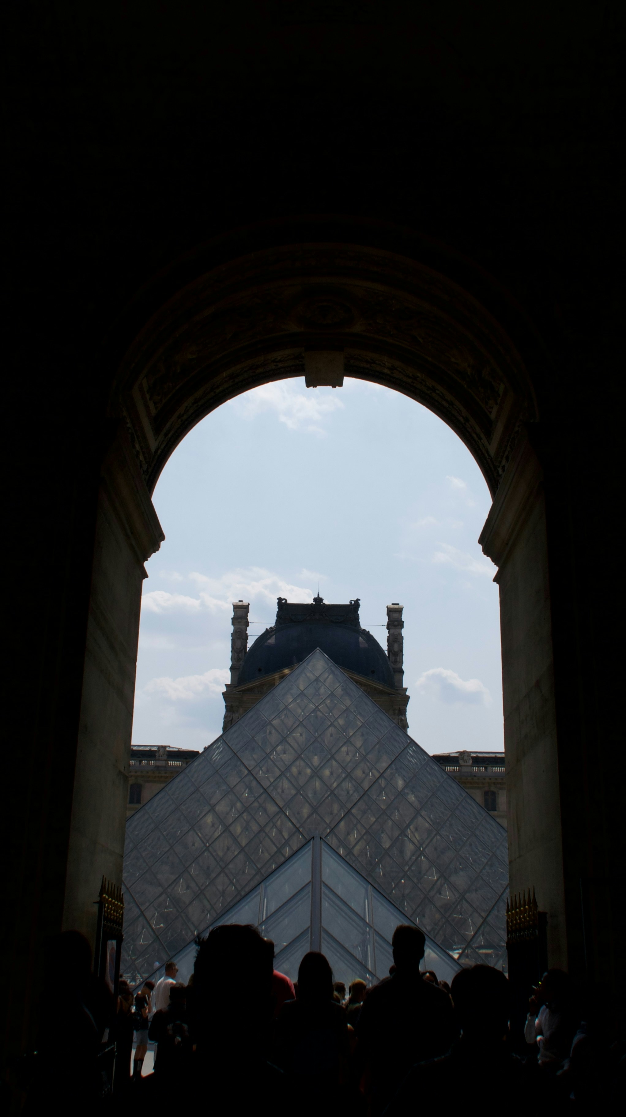 Gazing Through the Glass Pyramid: A Crowd Beside Parisian Light