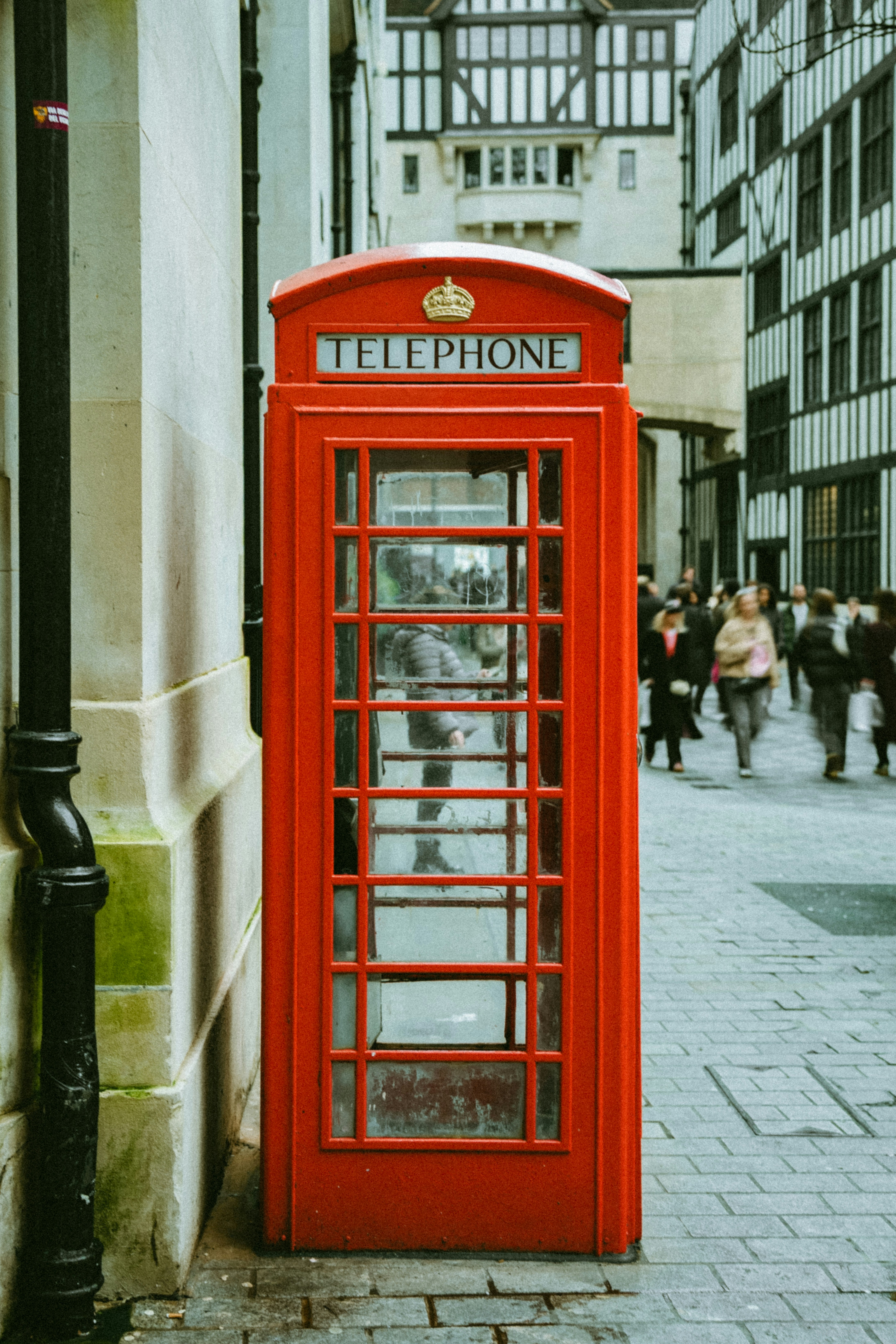 Crimson Toll: A Red British Phone Kiosk Amid a Busy Georgian Street