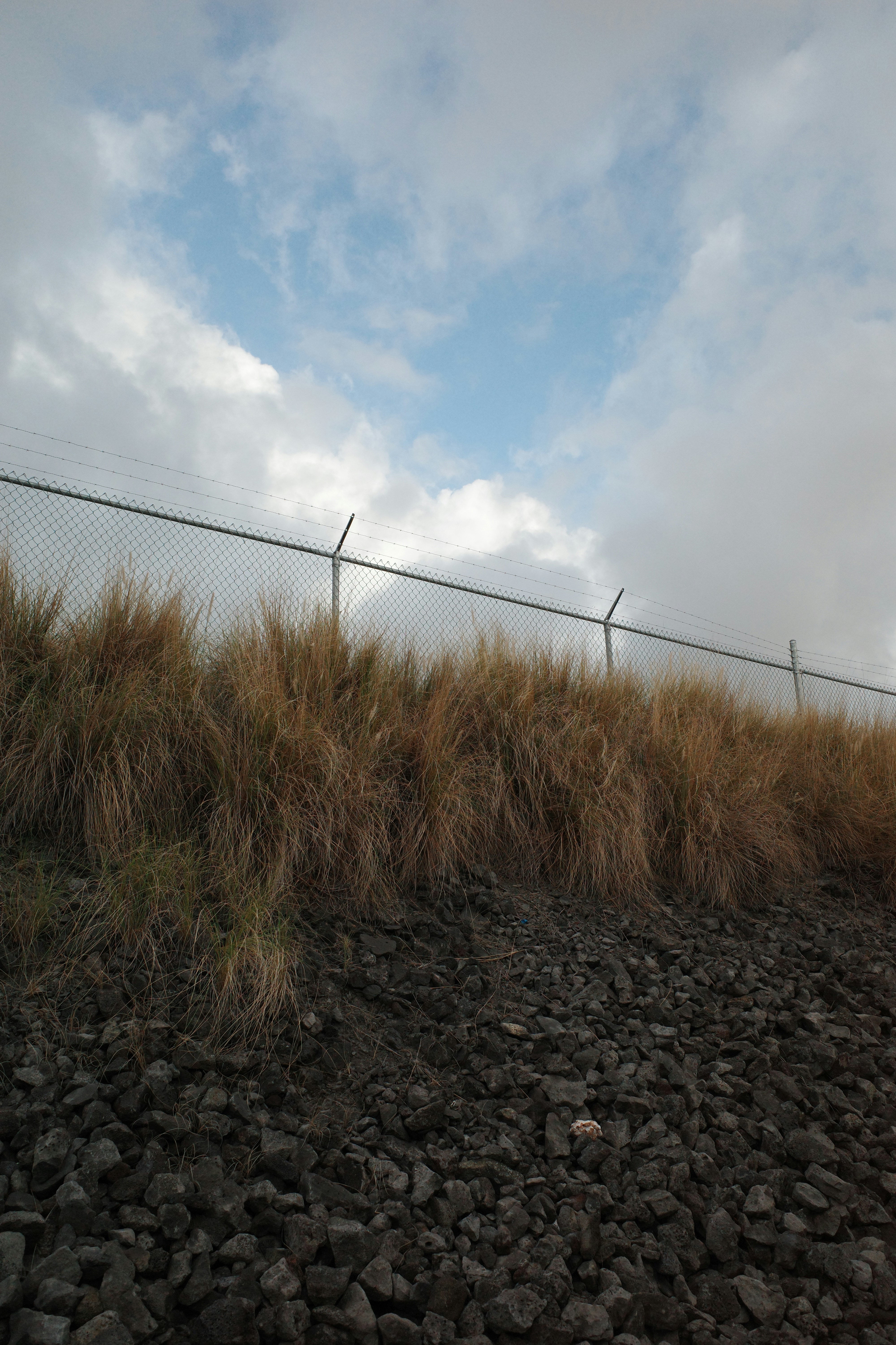 Fence across the grassy slope under a blue sky