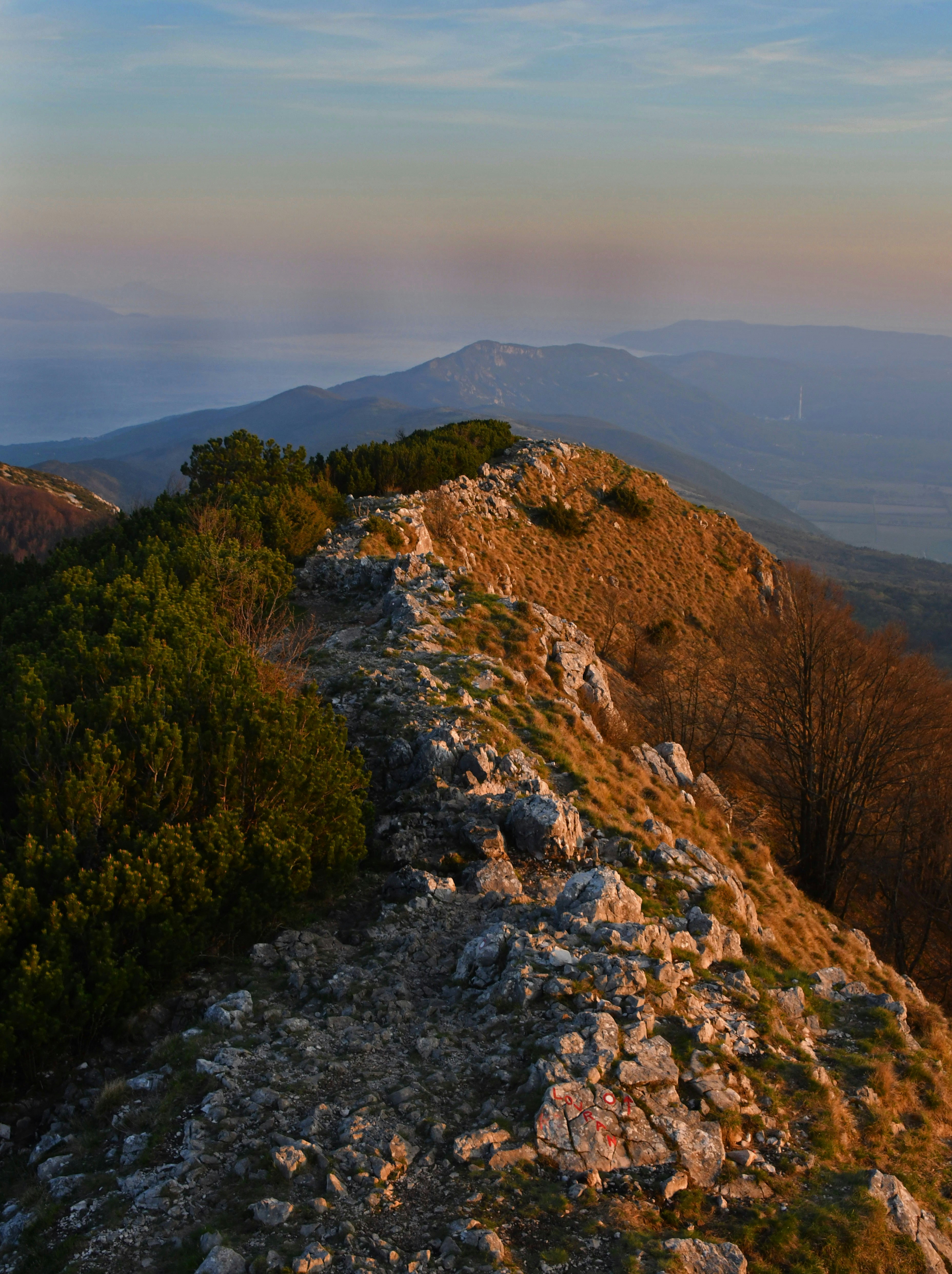 Rugged ridge of sunlit rocks under a fading alpine sky