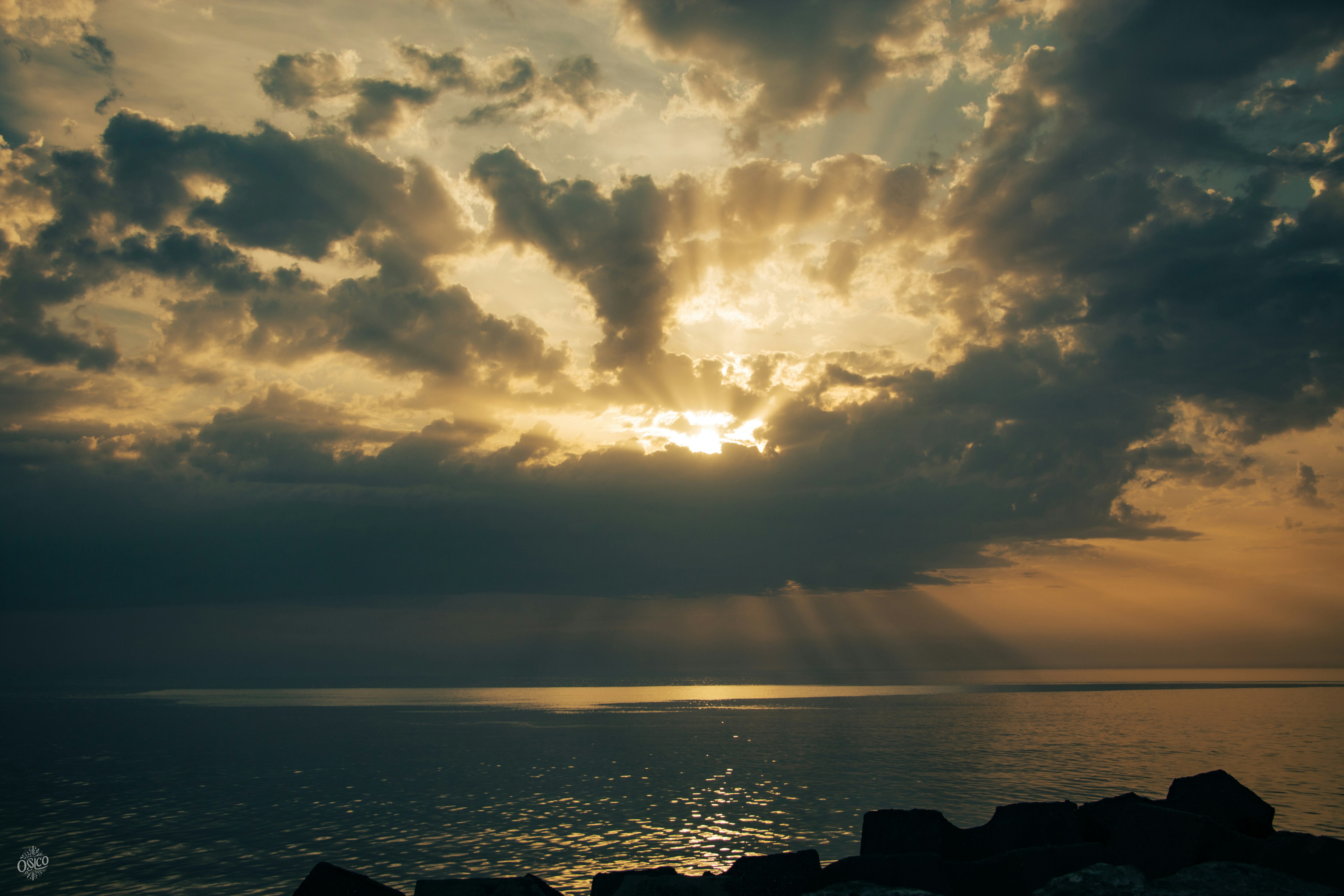 Sunlit Break: Rays Piercing a Quiet Horizon Over Gentle Waters