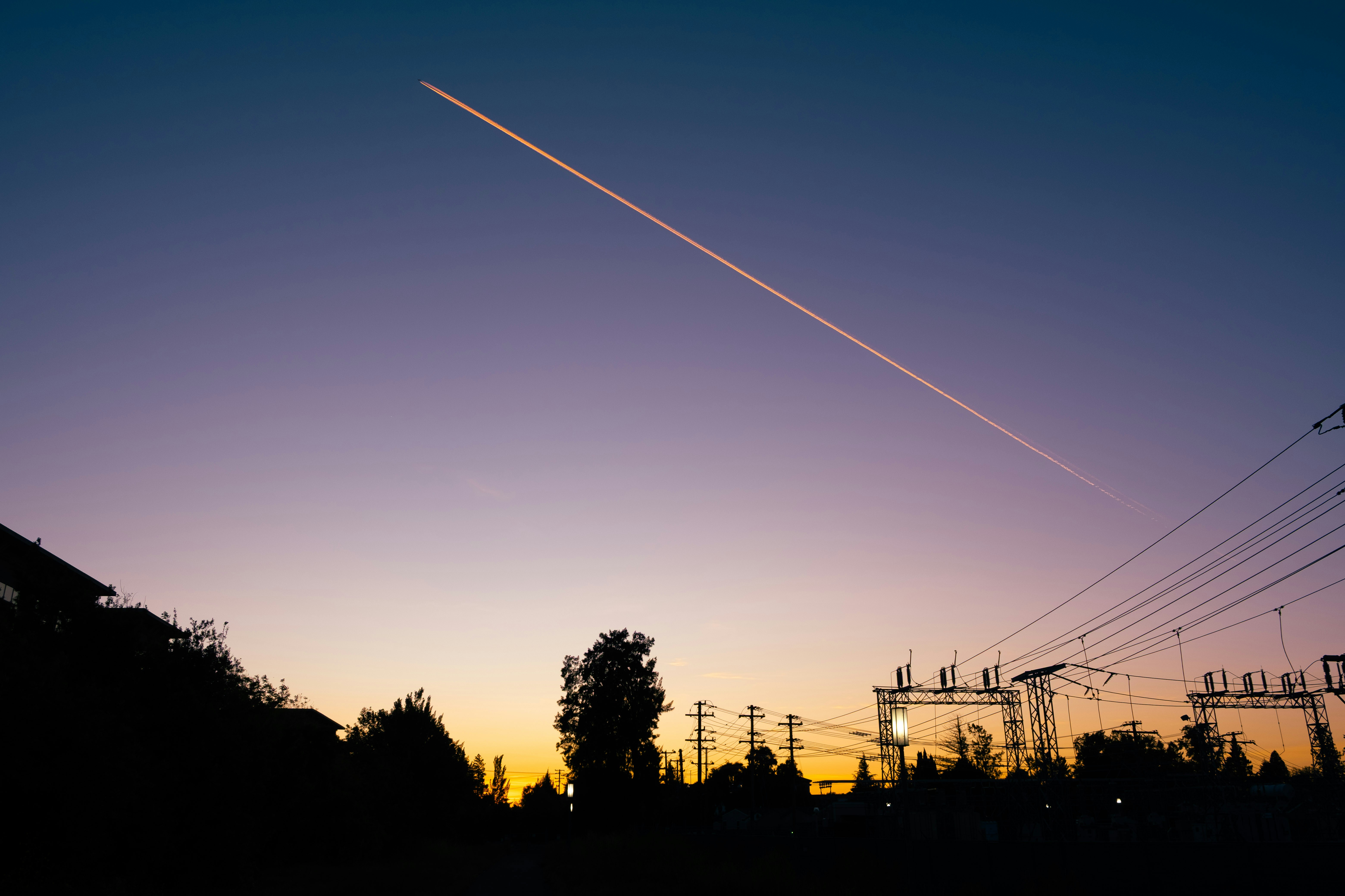 Jet Across the Dusk: a contrail stitched over a quiet industrial horizon