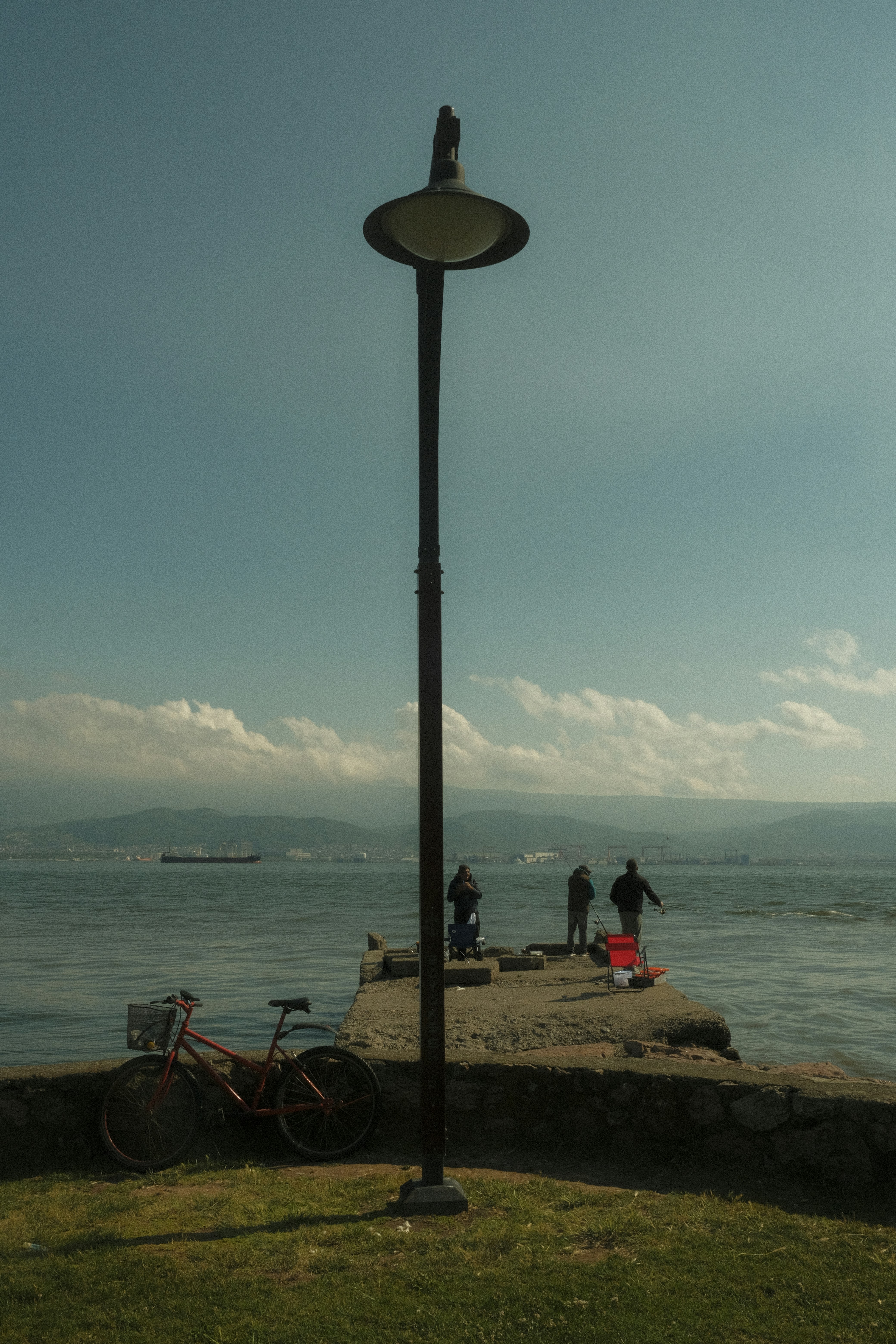 Midday pier: a lone lamppost anchors a quiet seaside scene