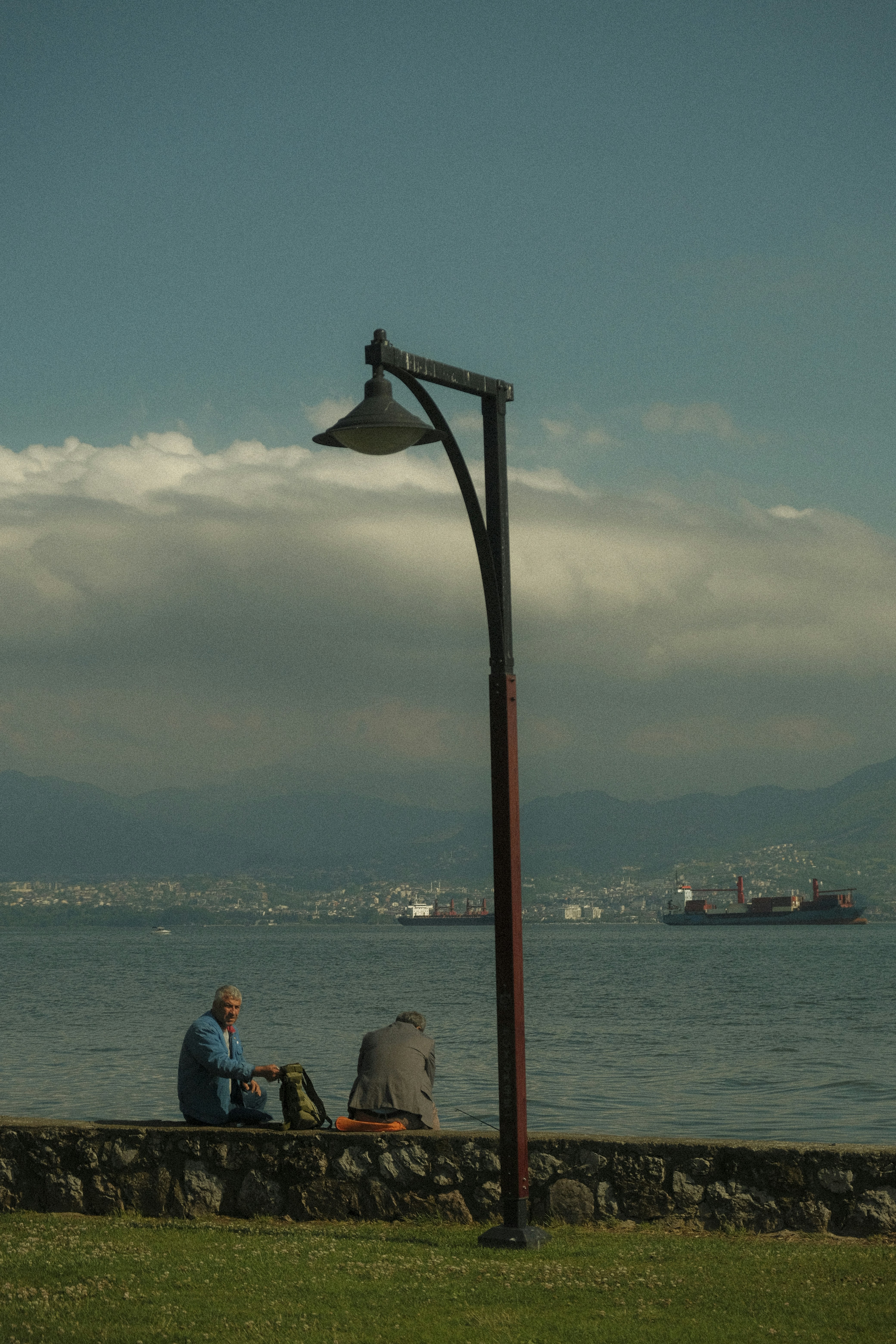 Quiet Harbor Bench: Two Figures by a Sea Wall Under a Street Lamp