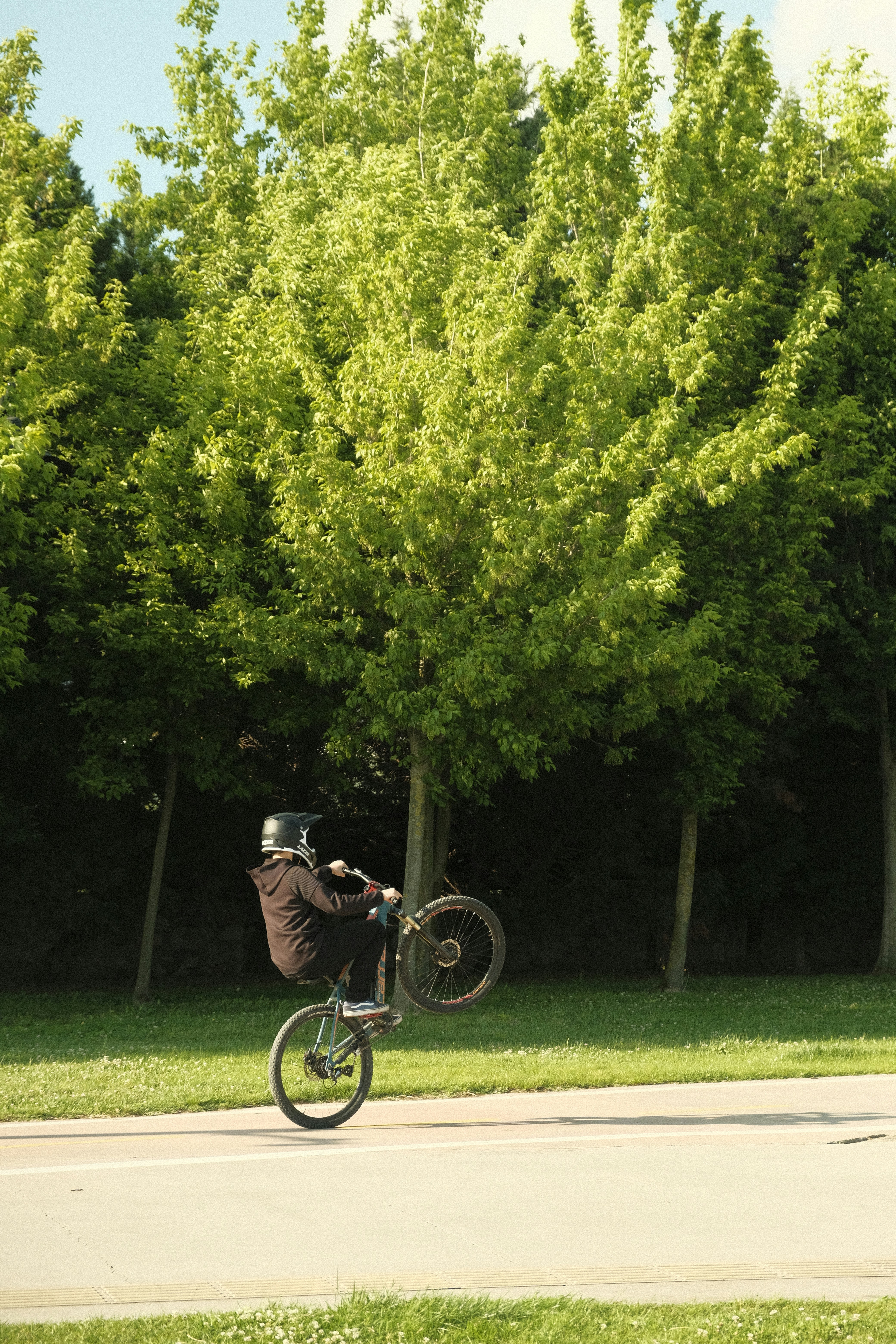 Wheelie of Focus: Rider Lifts a Bike in a Sunlit Park