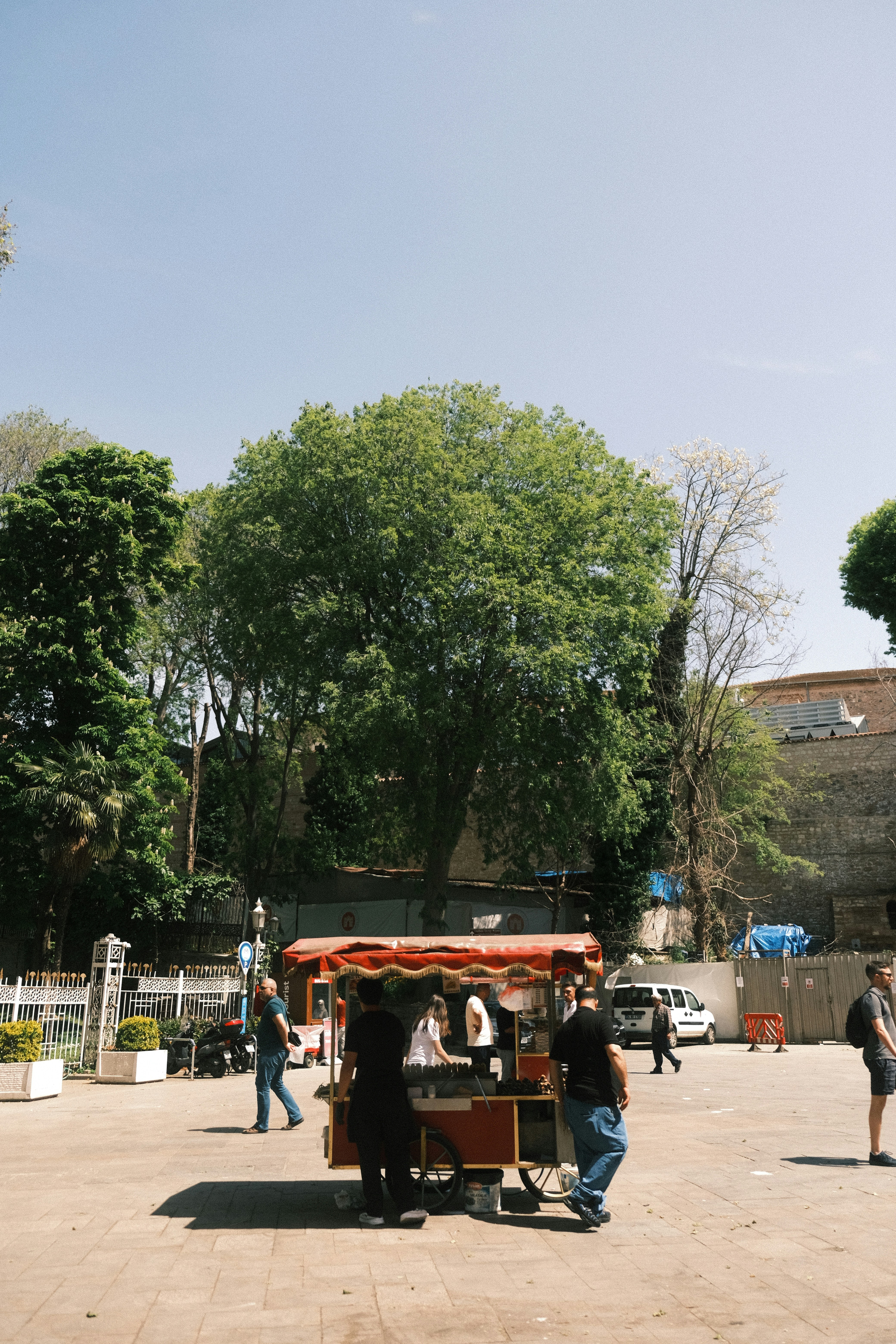 Street Vendor Under a Red Canopy Framed by Shaded Trees