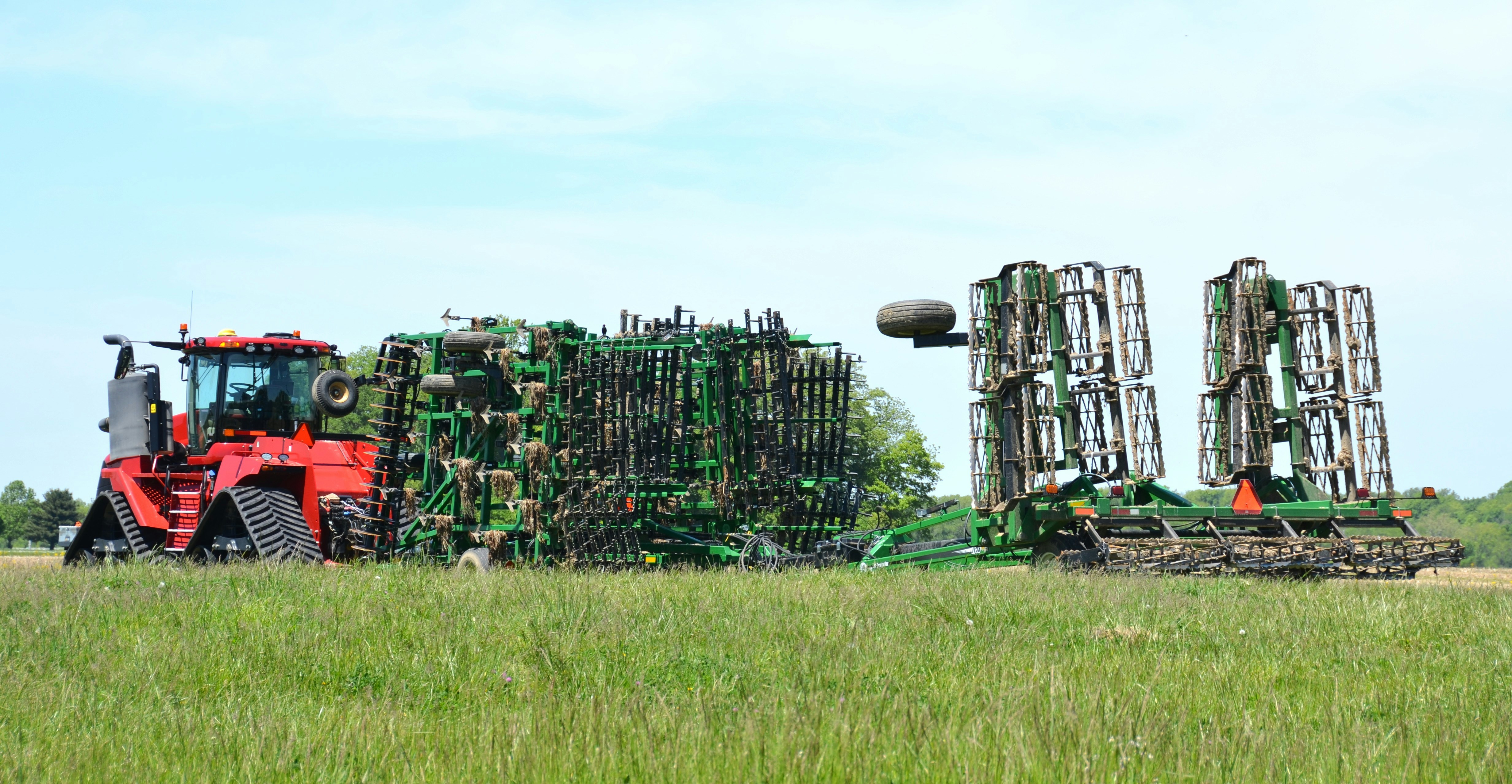 Red Tractor Sentinel with Harvesting Equipment on the Horizon