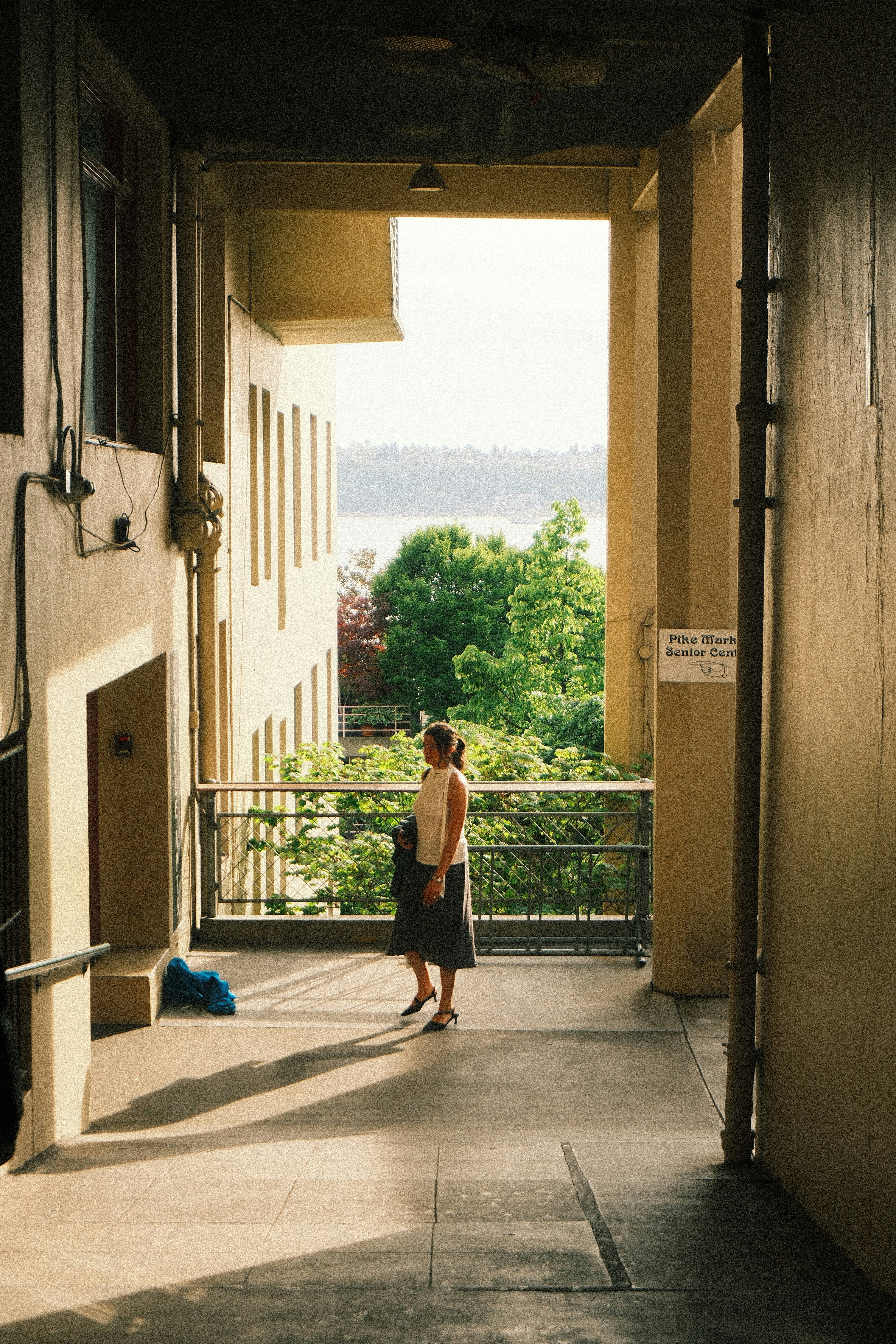 Quiet Balcony Moment: A Woman in a Sunlit Corridor