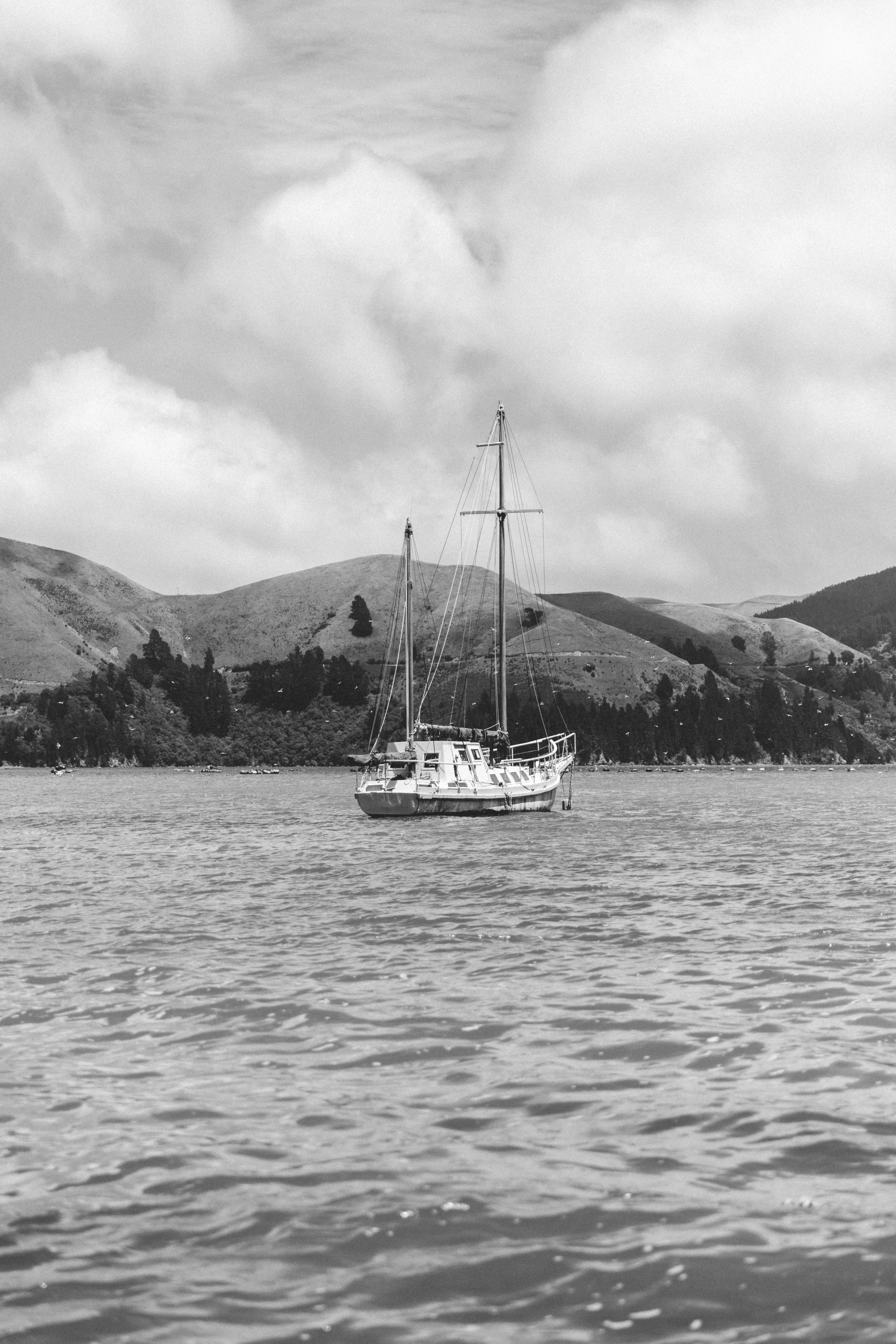 Sailboat anchored in a calm bay beneath rolling hills