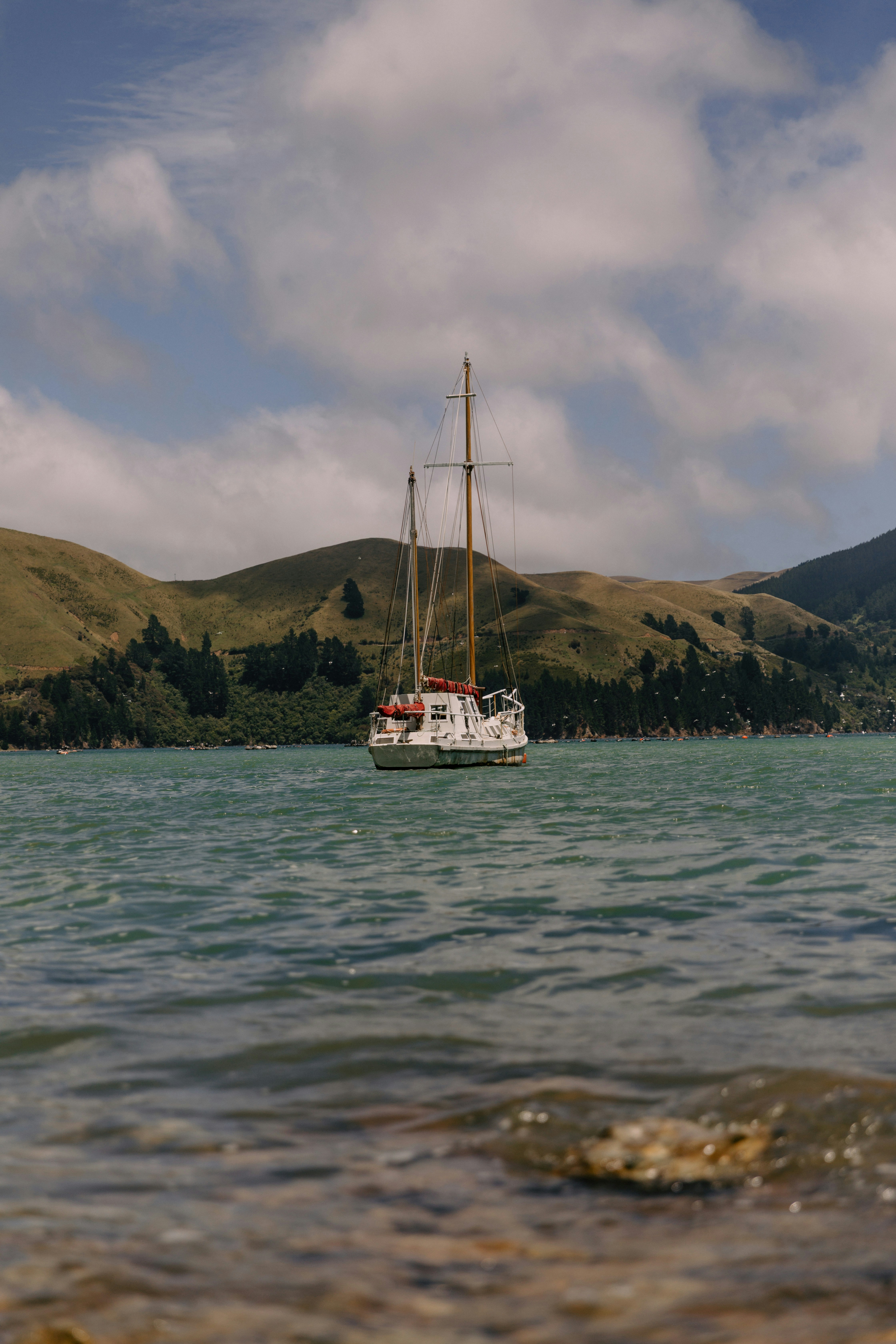Sailing in Calm Fjord: A Lone Vessel Anchored Before Green Hills