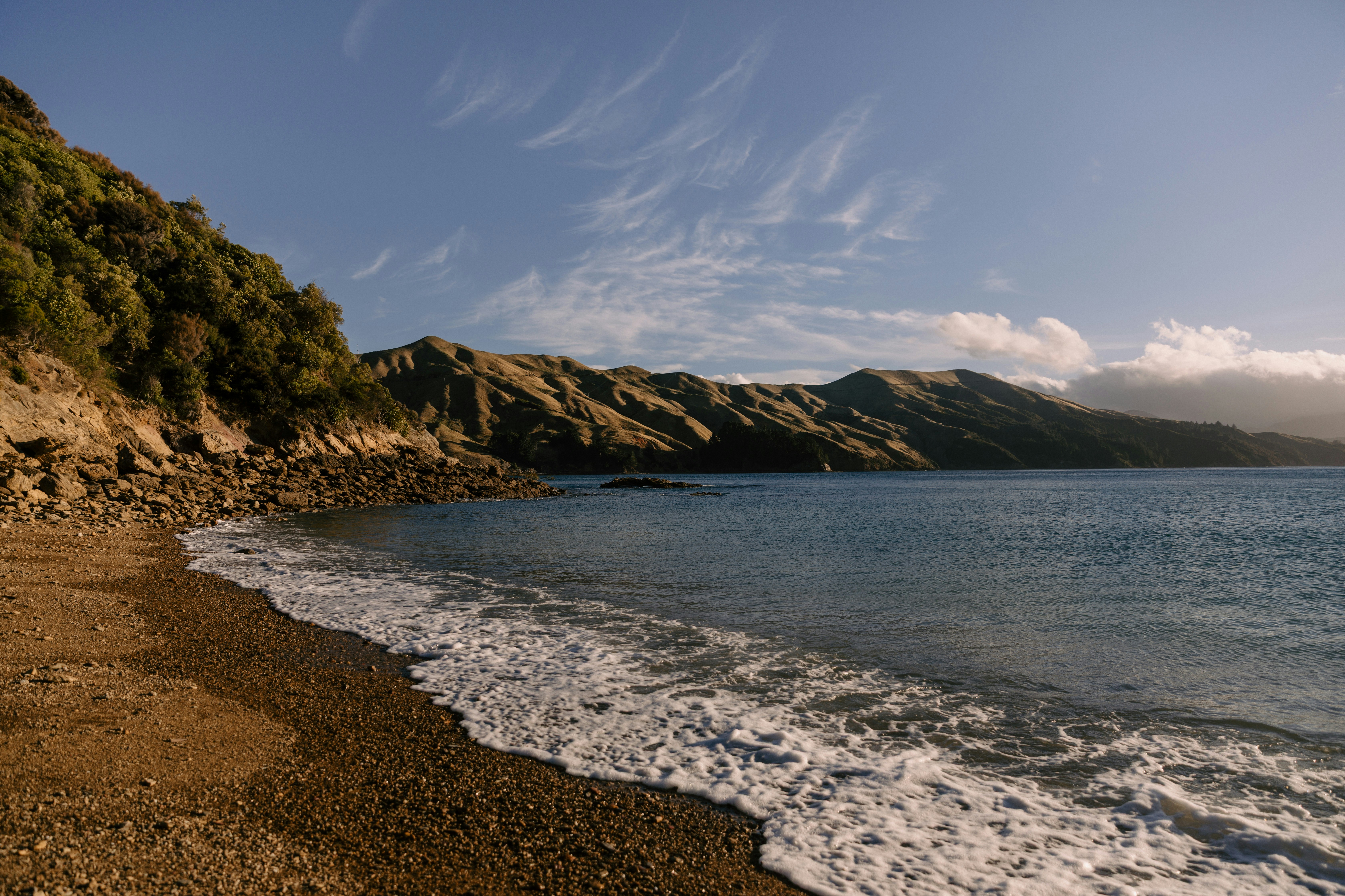 Sunlit shoreline folding into distant hills