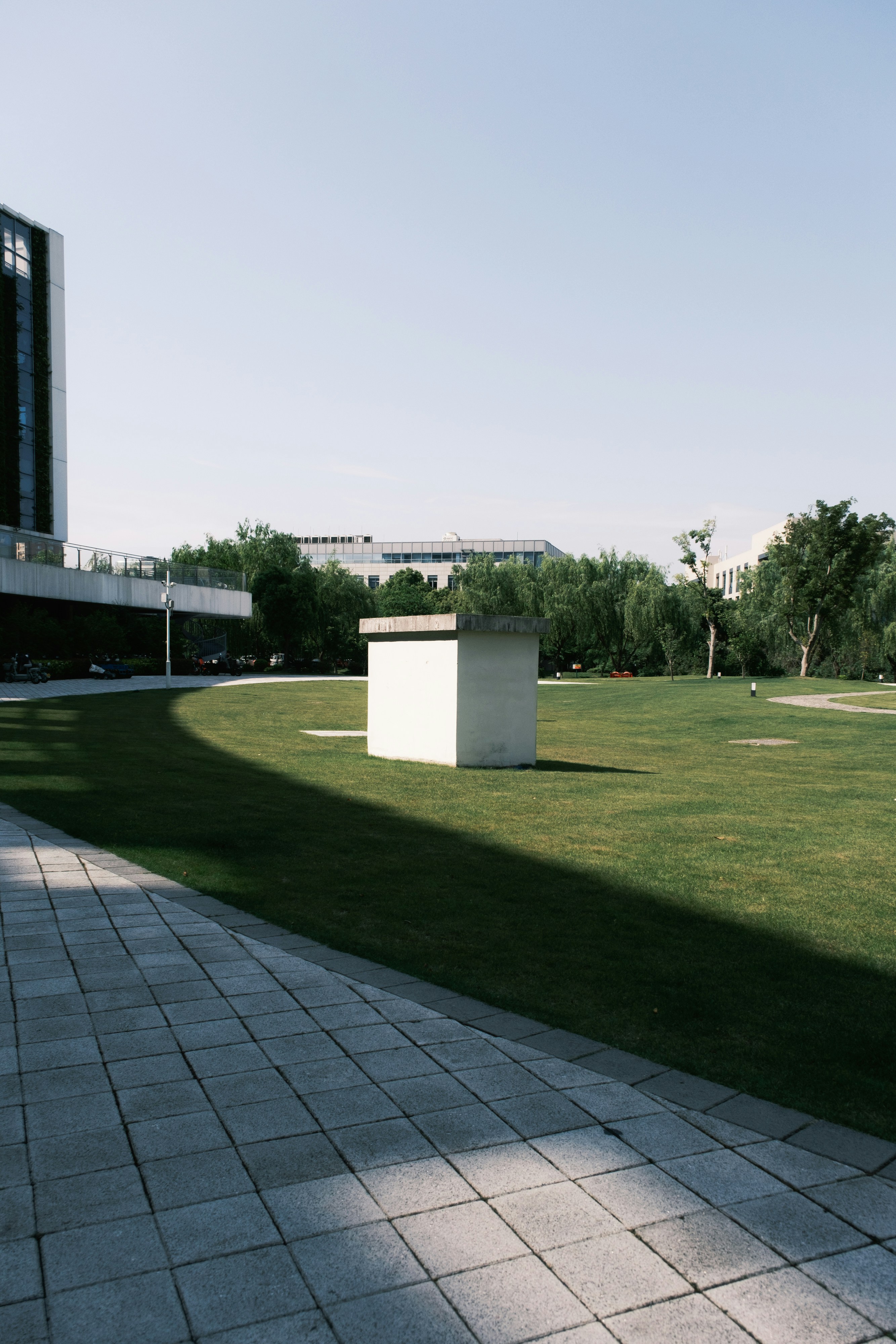 Shadowed Lawn and Concrete Cube Under a Clear Sky