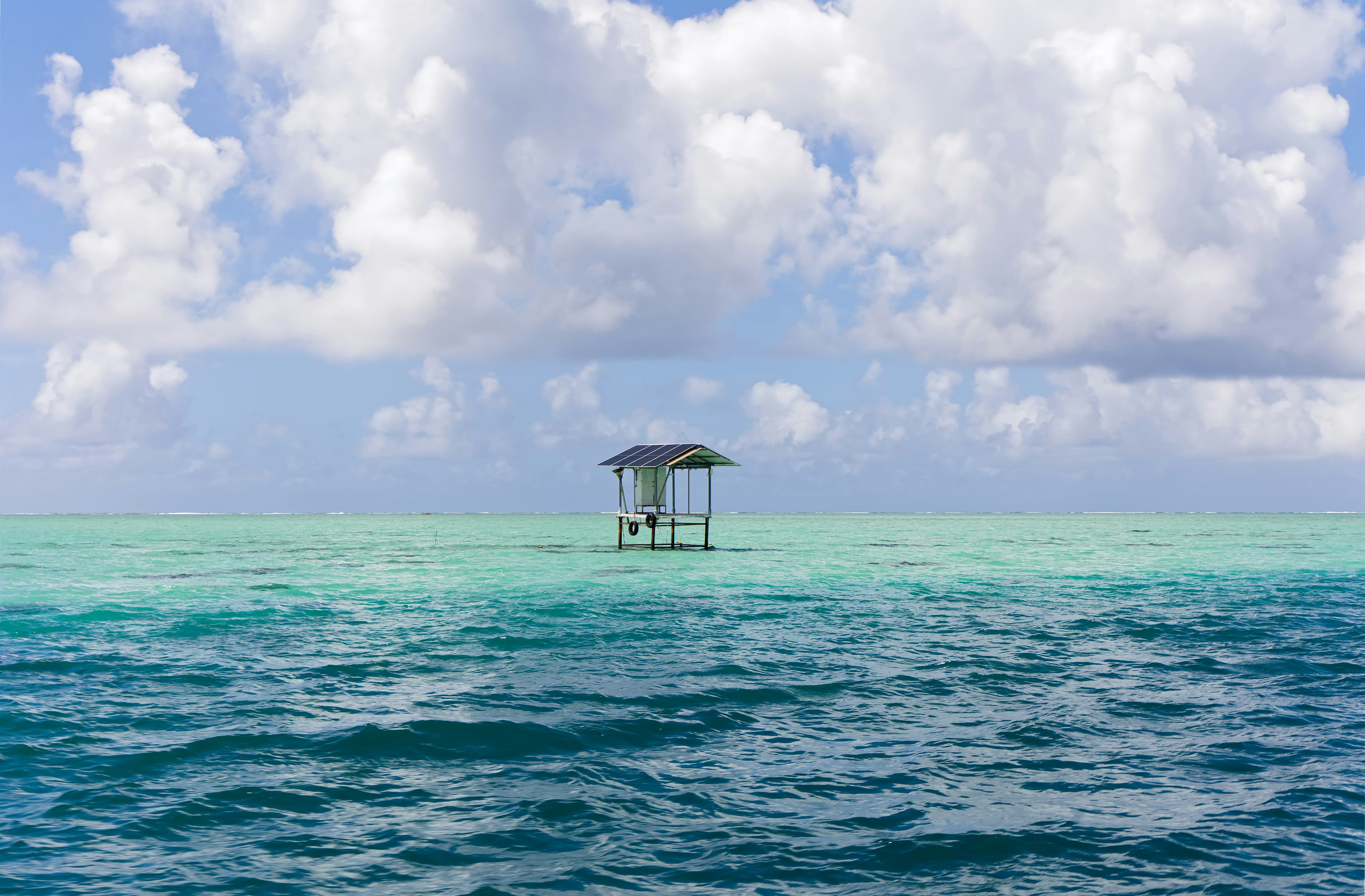 Remote Ocean Shelter: A solitary hut perched above turquoise shallows