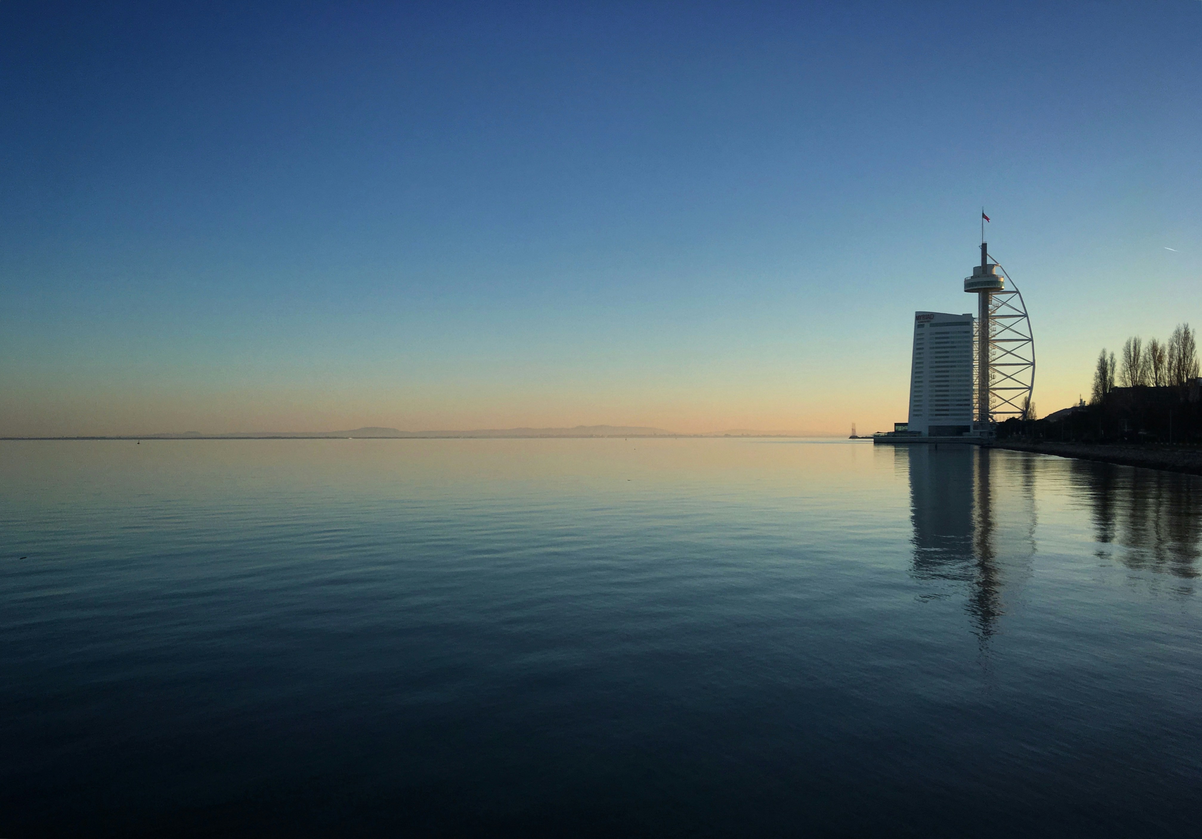 Harbor Silhouette at Dusk: A Quiet Beacon by the Calm Sea