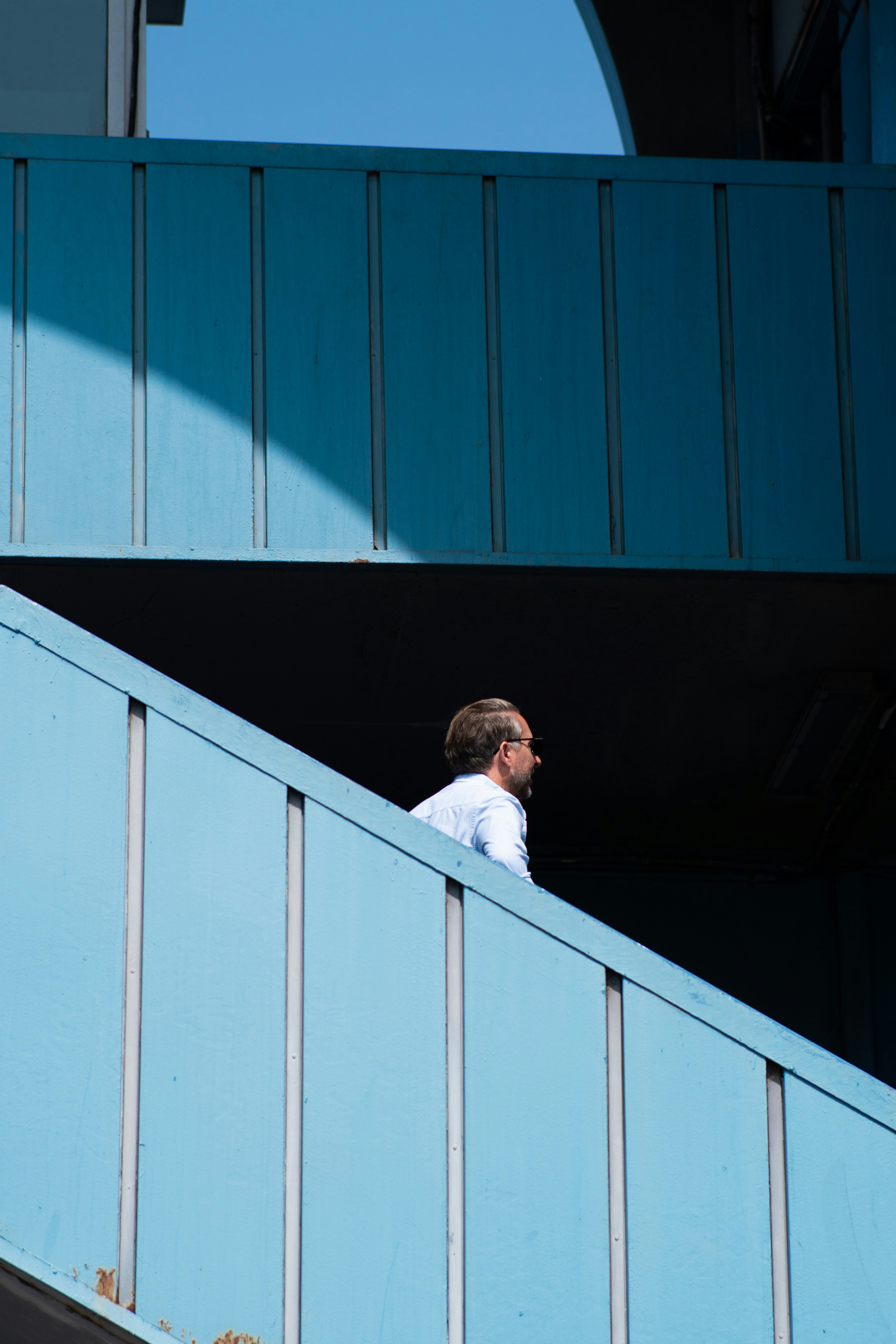 Blue Staircase Stranger: A Man Ascends the Sea of Cyan