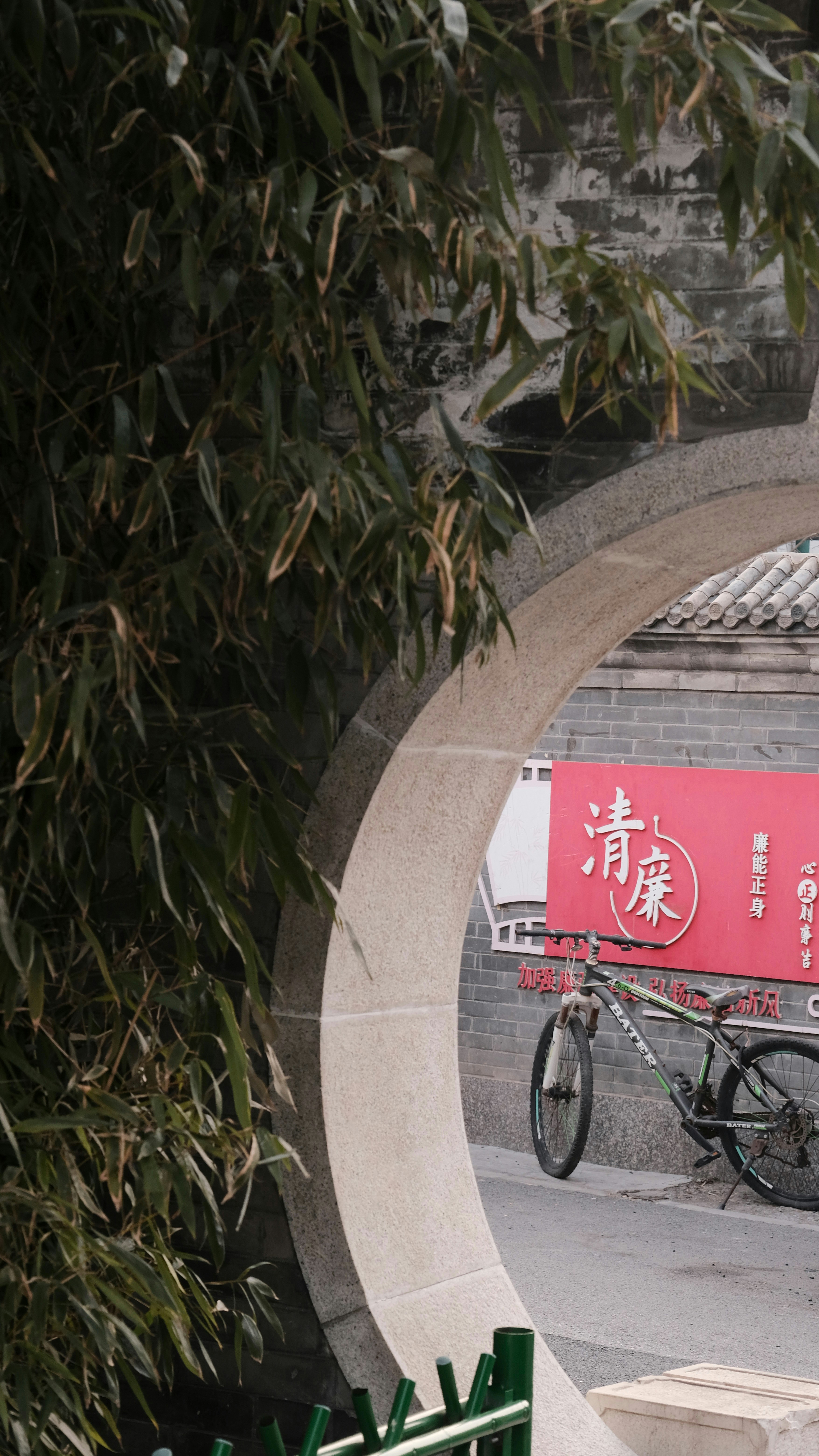 Circular Stone Arch Framing a Street Bicycle by a Red Sign