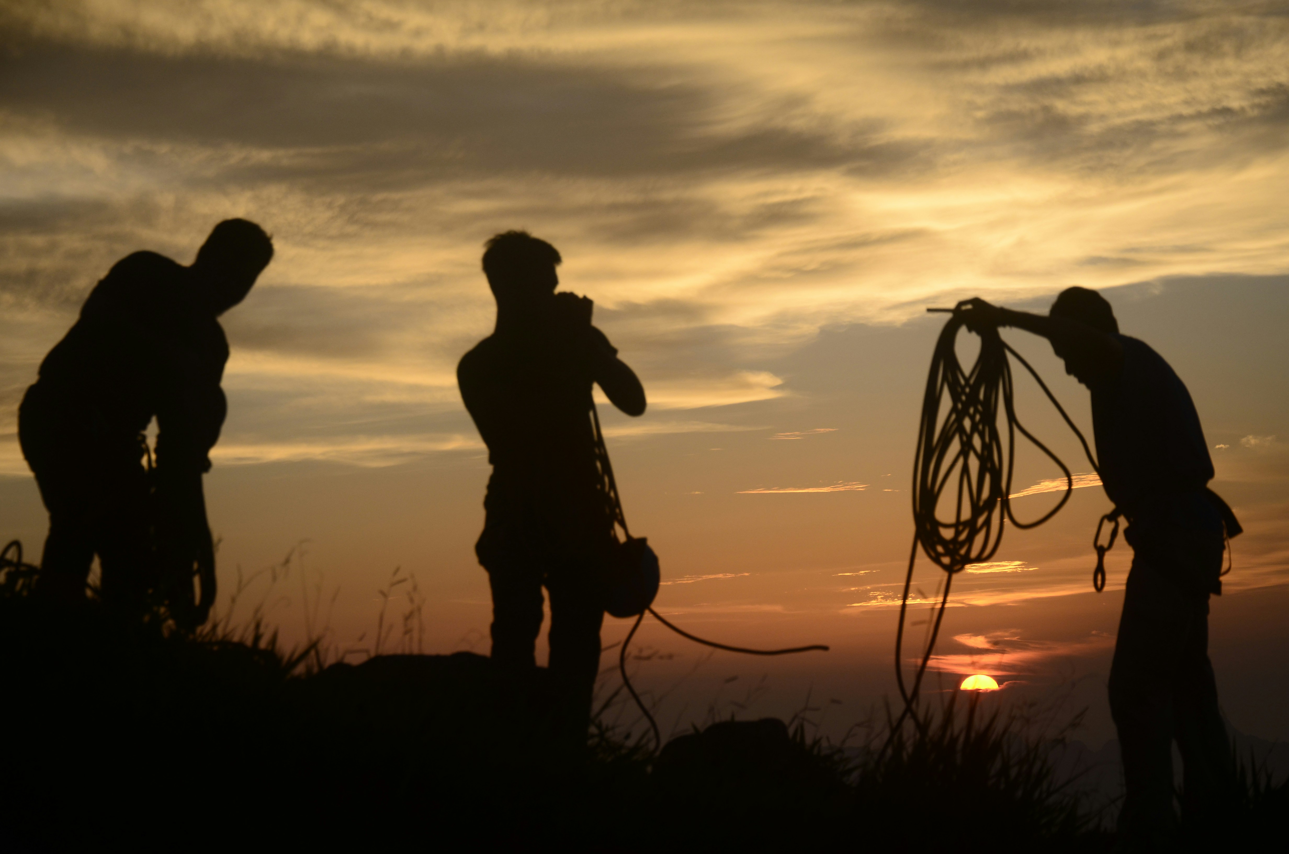 Silhouetted Crew at Dusk: Ropes and Machinery Against a Golden Horizon