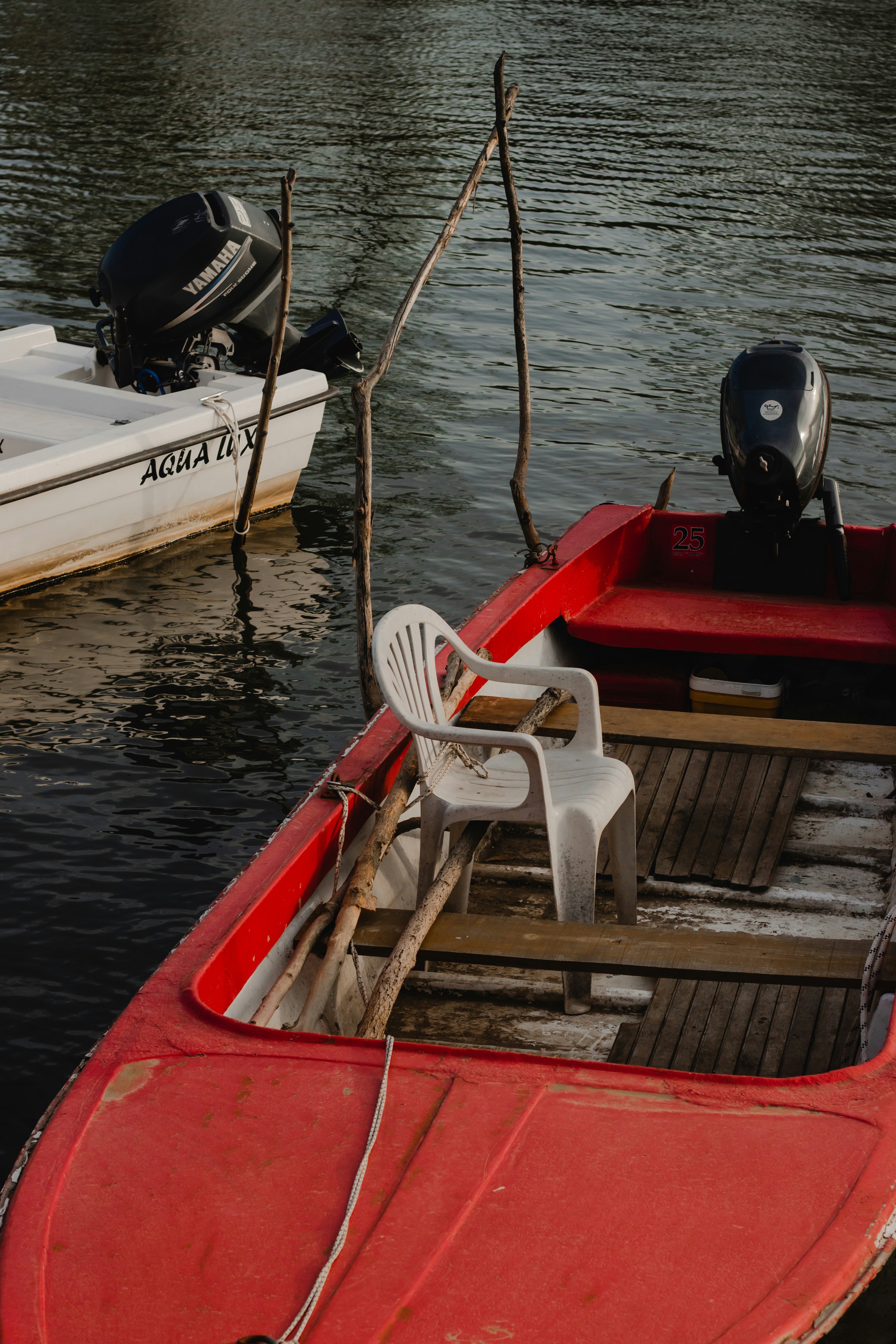 Red Boat Sanctuary: A Quiet Dock Scene with White Plastic Chair