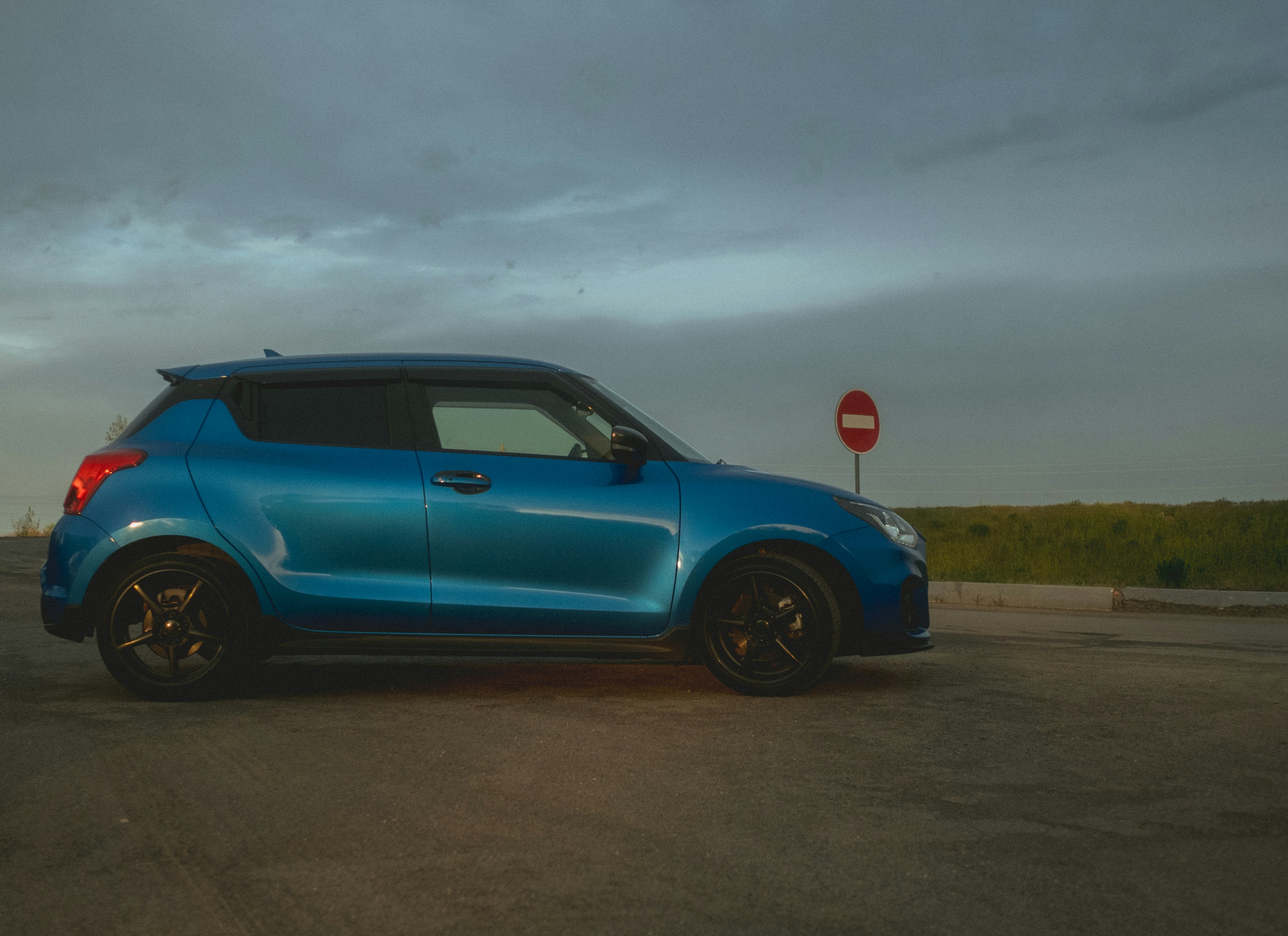Blue hatchback under an open sky: a quiet roadside portrait
