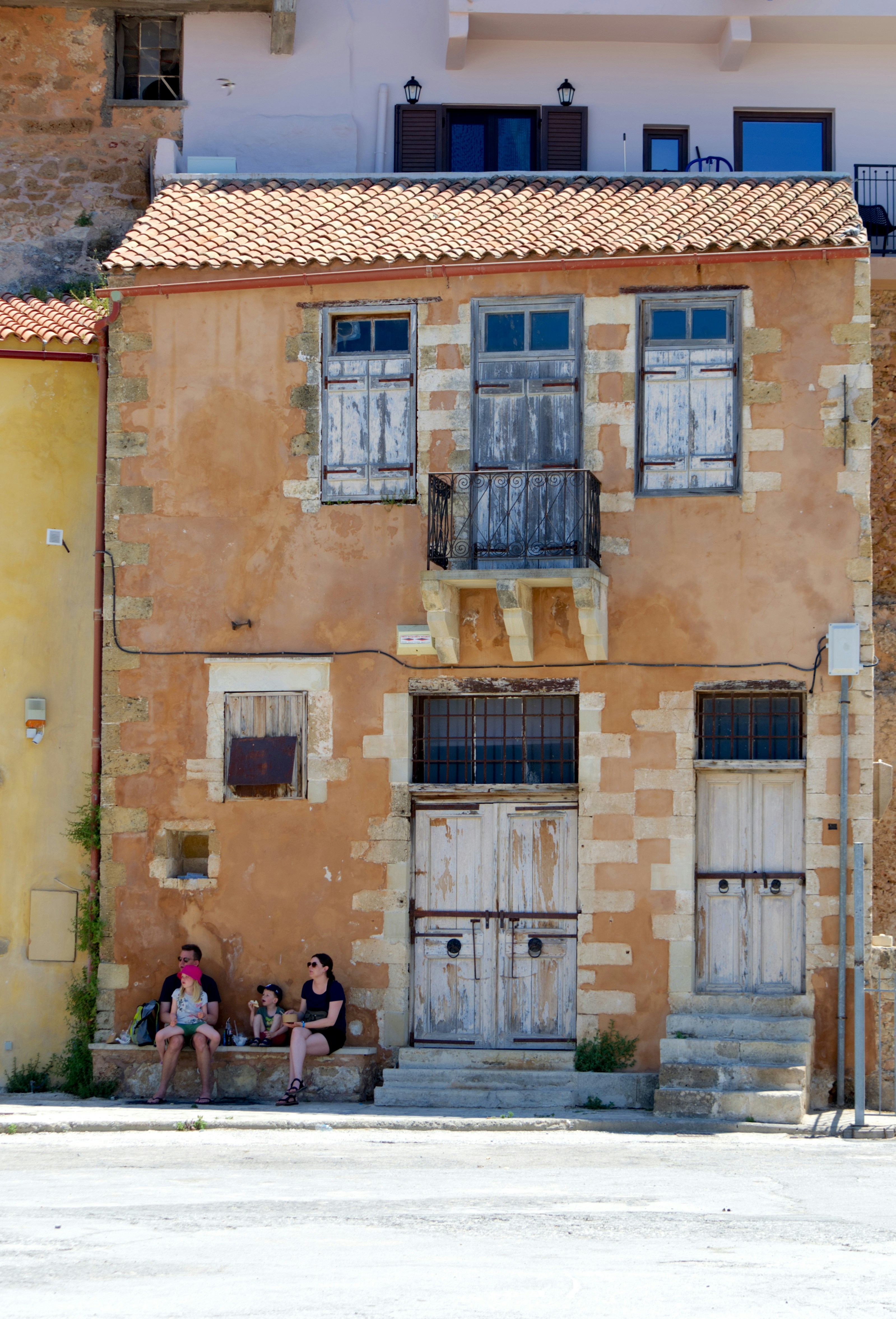 Sunlit Facade and Village Family on a Quiet Street