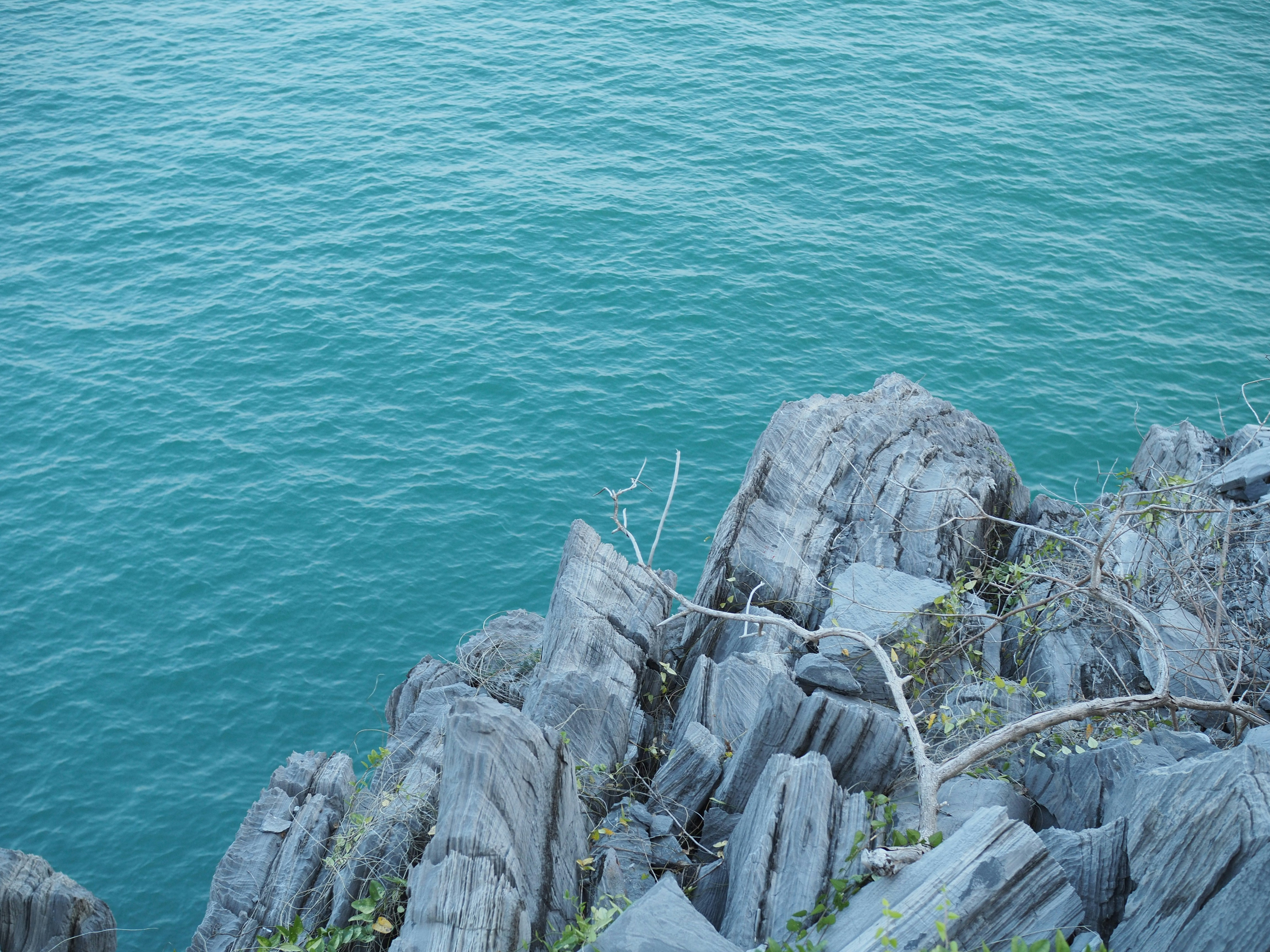 Jagged shoreline of slate rocks meeting turquoise sea