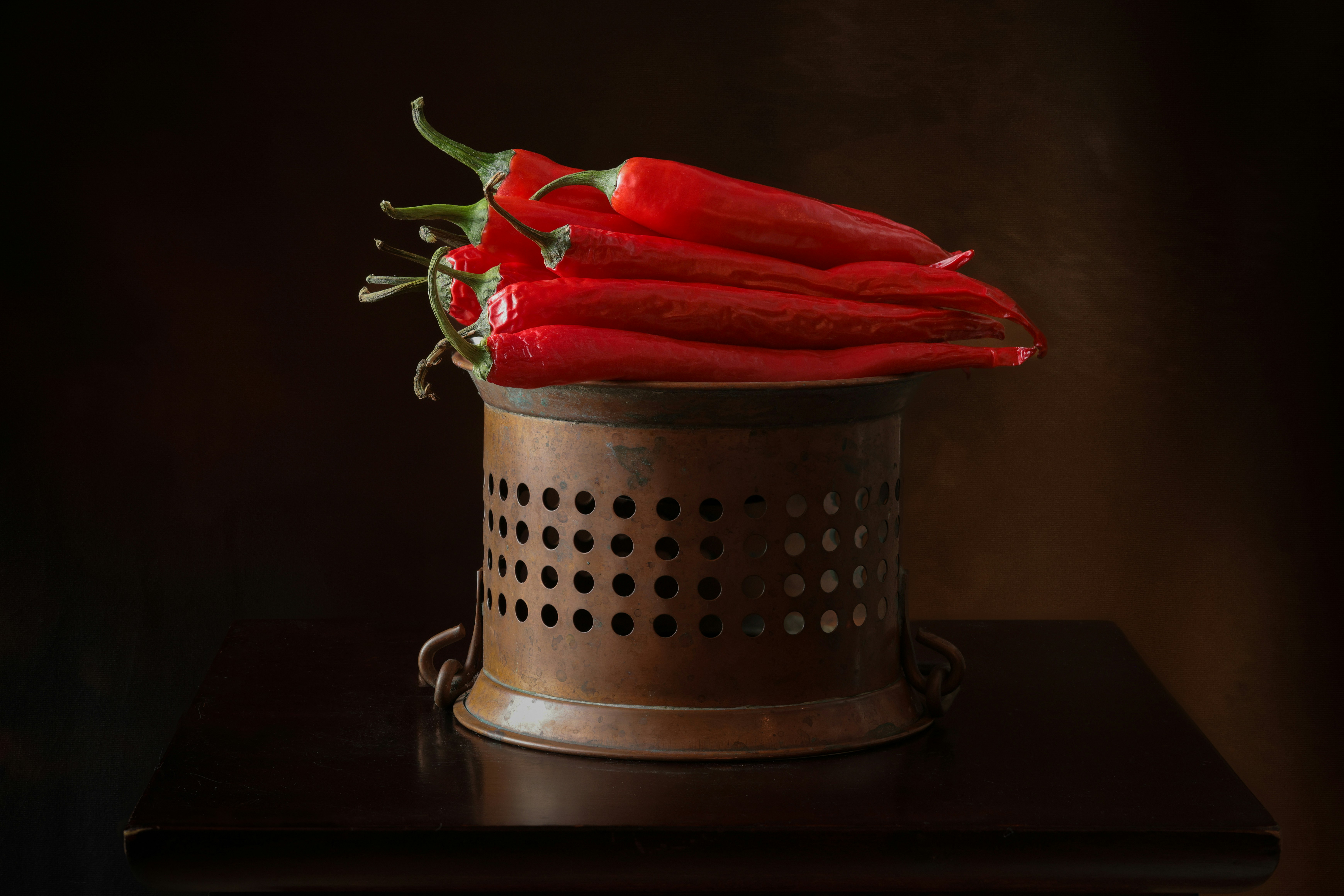 Red Heat on Copper: Peppers Resting on a Perforated Vessel