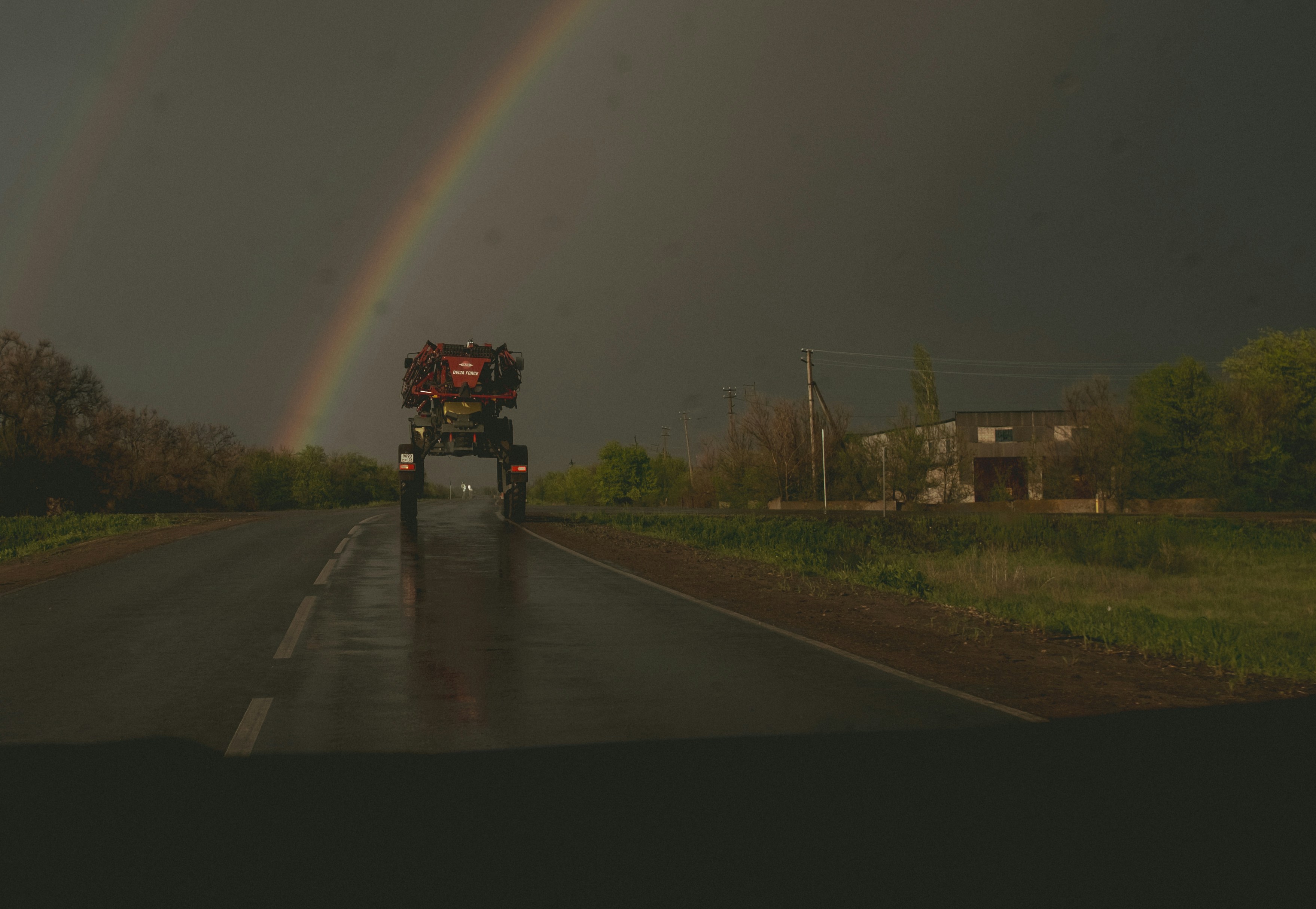 Double Rainbow Over Wet Highway: A Lone Carriage Heads Toward Colorful Skies