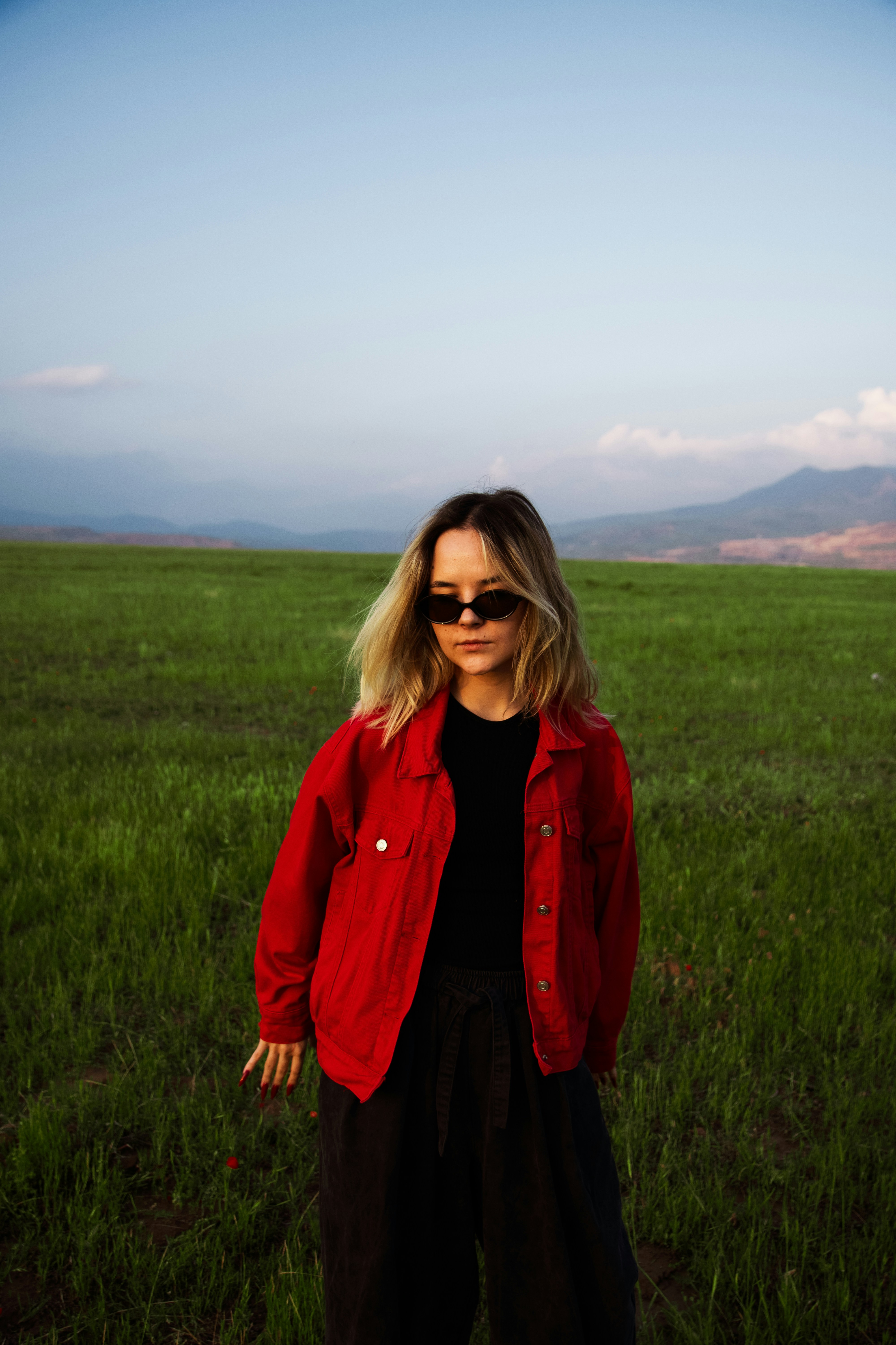 Red Jacket in a Green Meadow Under Expansive Sky