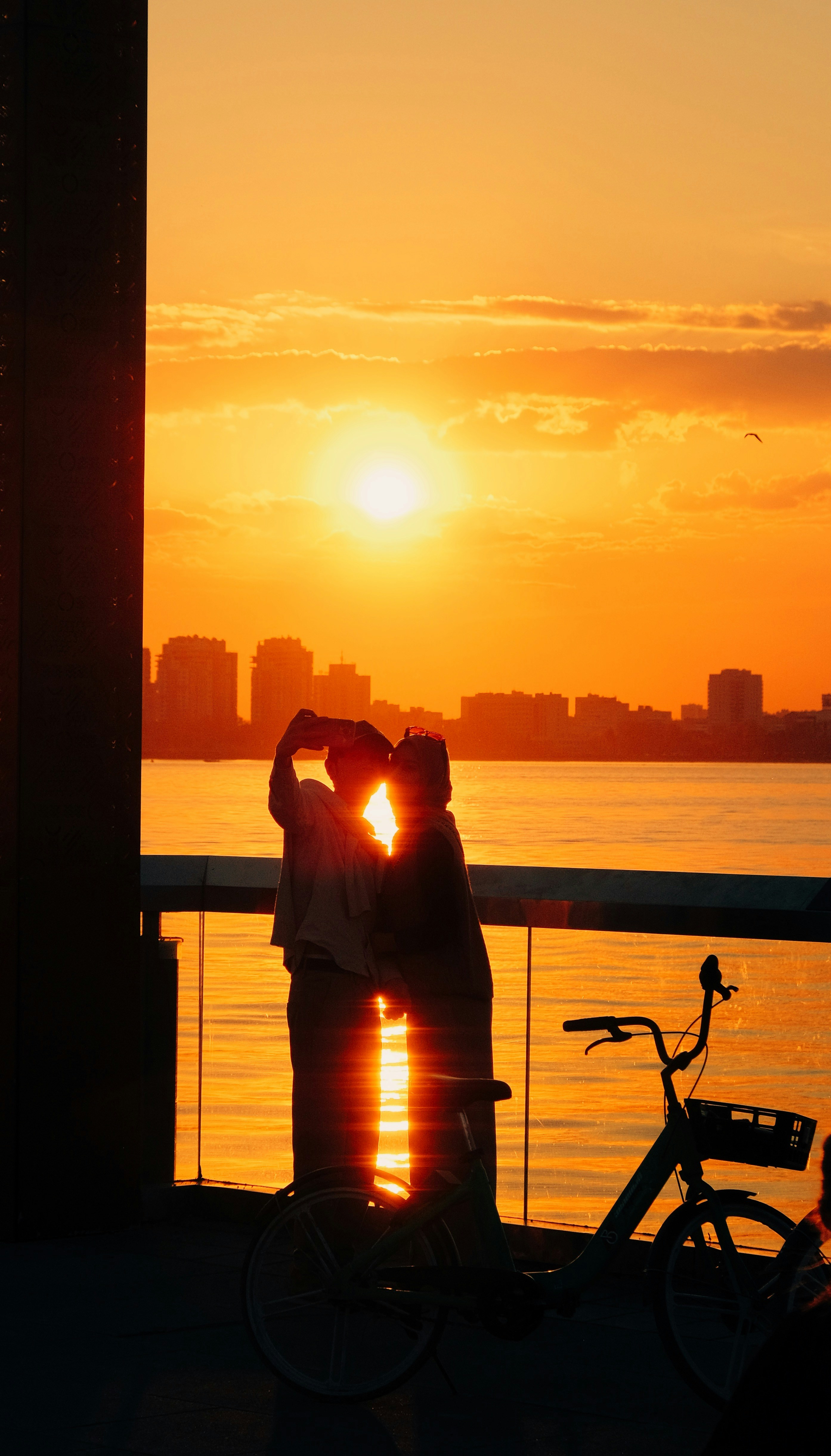 Sunset Silhouette: Lovers Framing a Moment by the Riverside