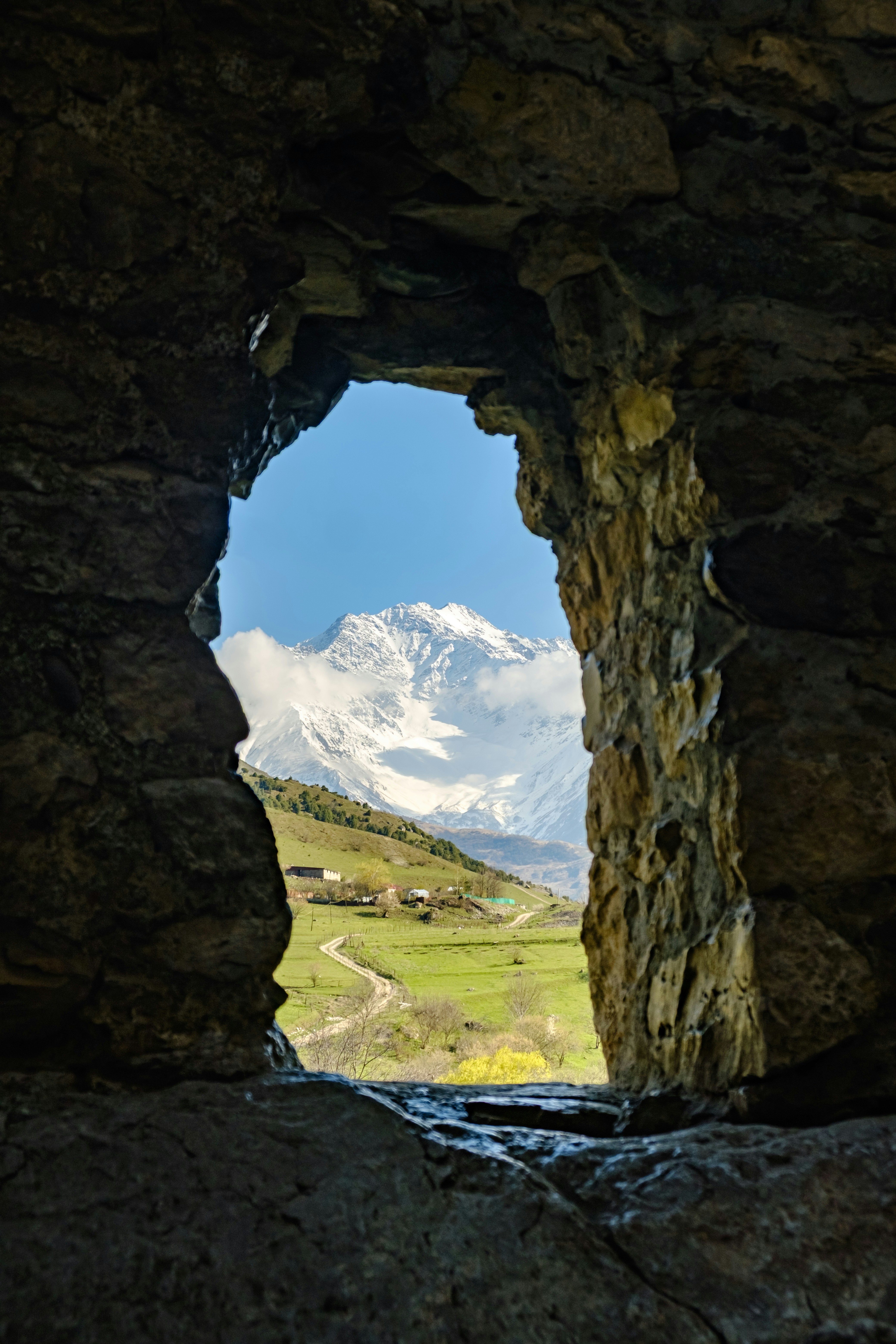 View through an ancient rock window to a snow-capped peak and valley