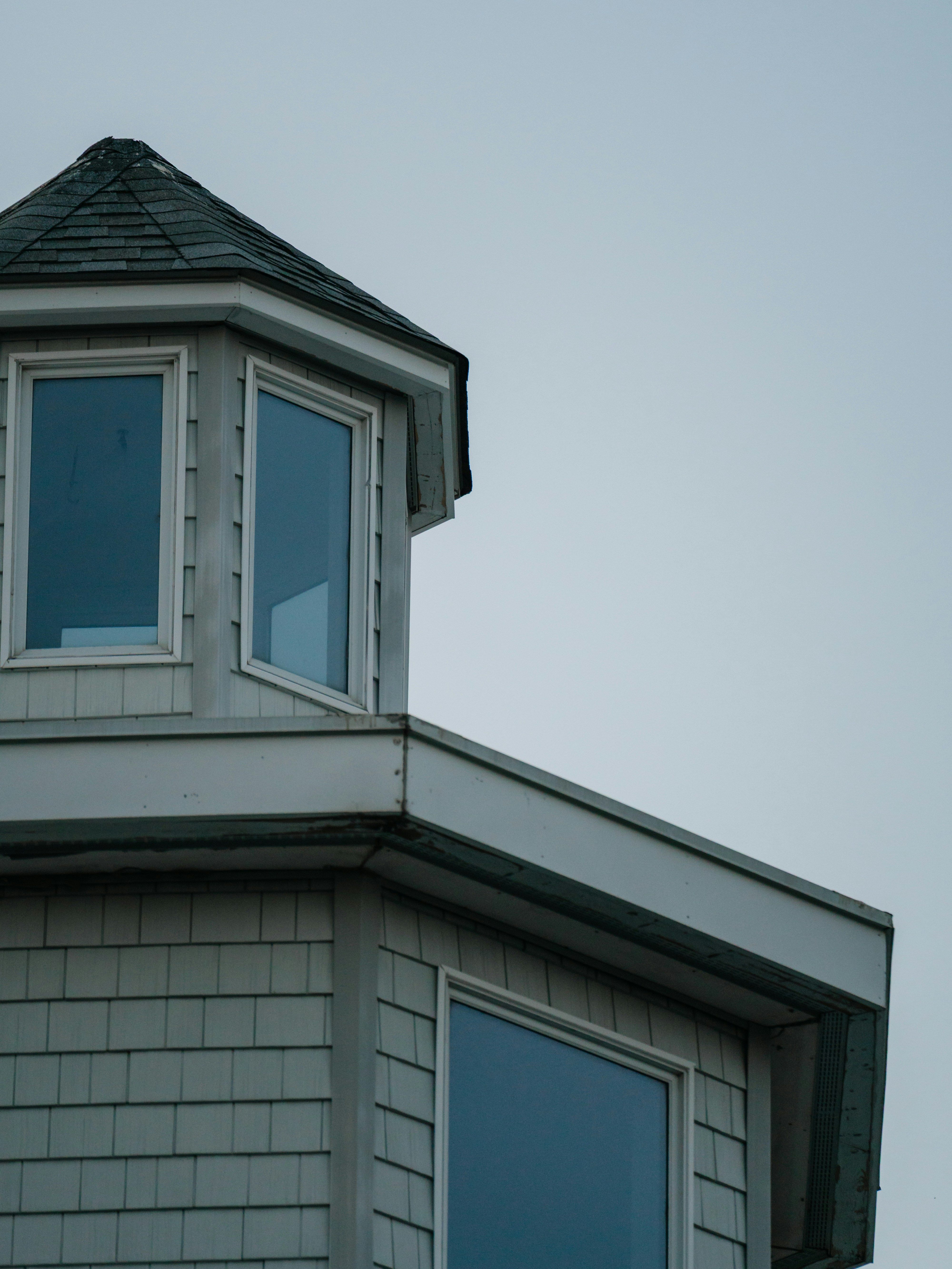 Corner Turret: A Quiet Crest of a Shingled House Against a Pale Sky