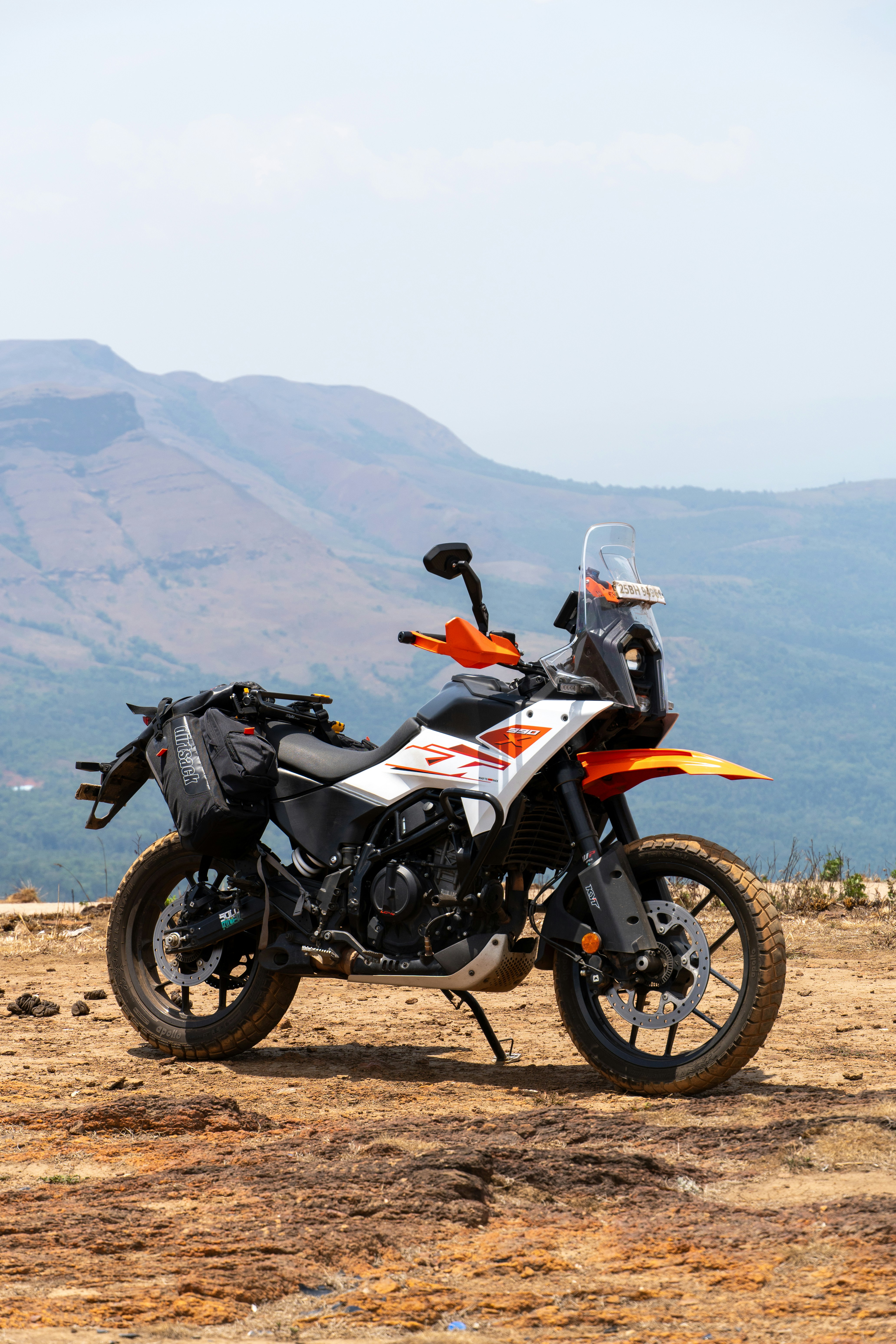 Adventure Rally: Orange-Kitted Dual-Sport Resting at a Ledge Overlooking Distant Valleys