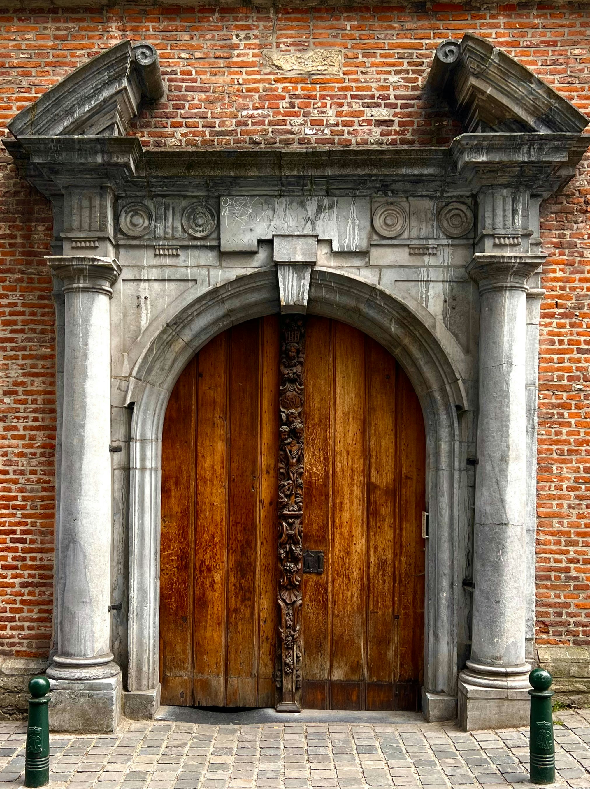 Weathered archway door: a carved stone frame framing warm wooden double doors