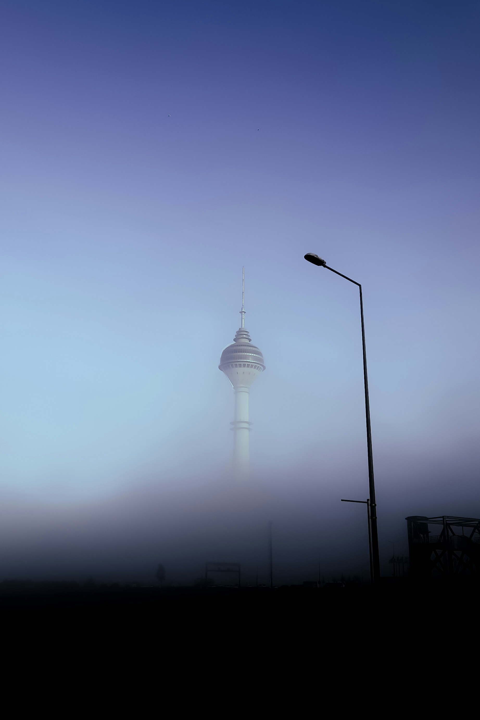 Mistbound Spire: A Streetlight and Towerrise Through Fog